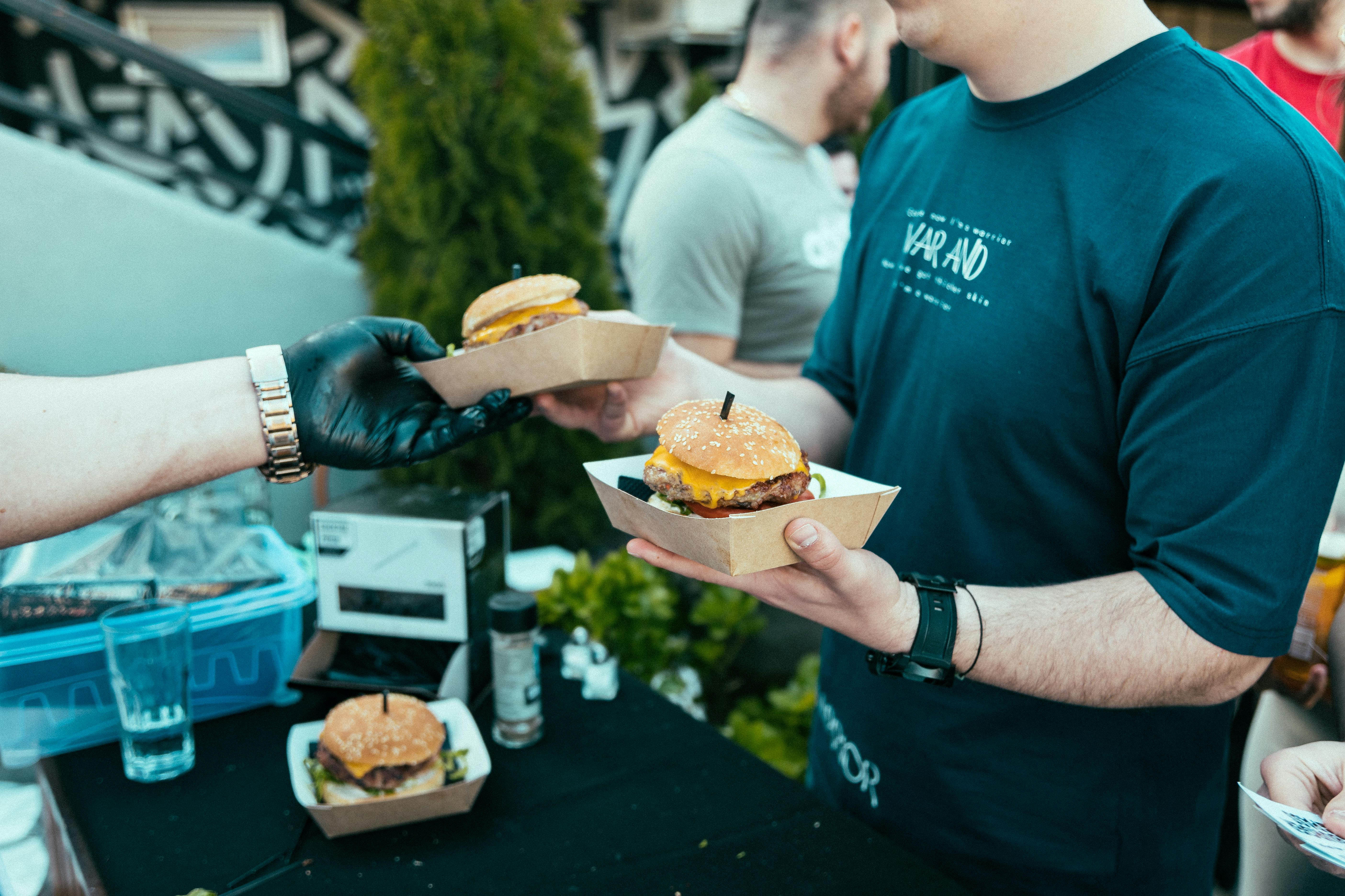 Man Standing and Taking Boxes of Burgers · Free Stock Photo
