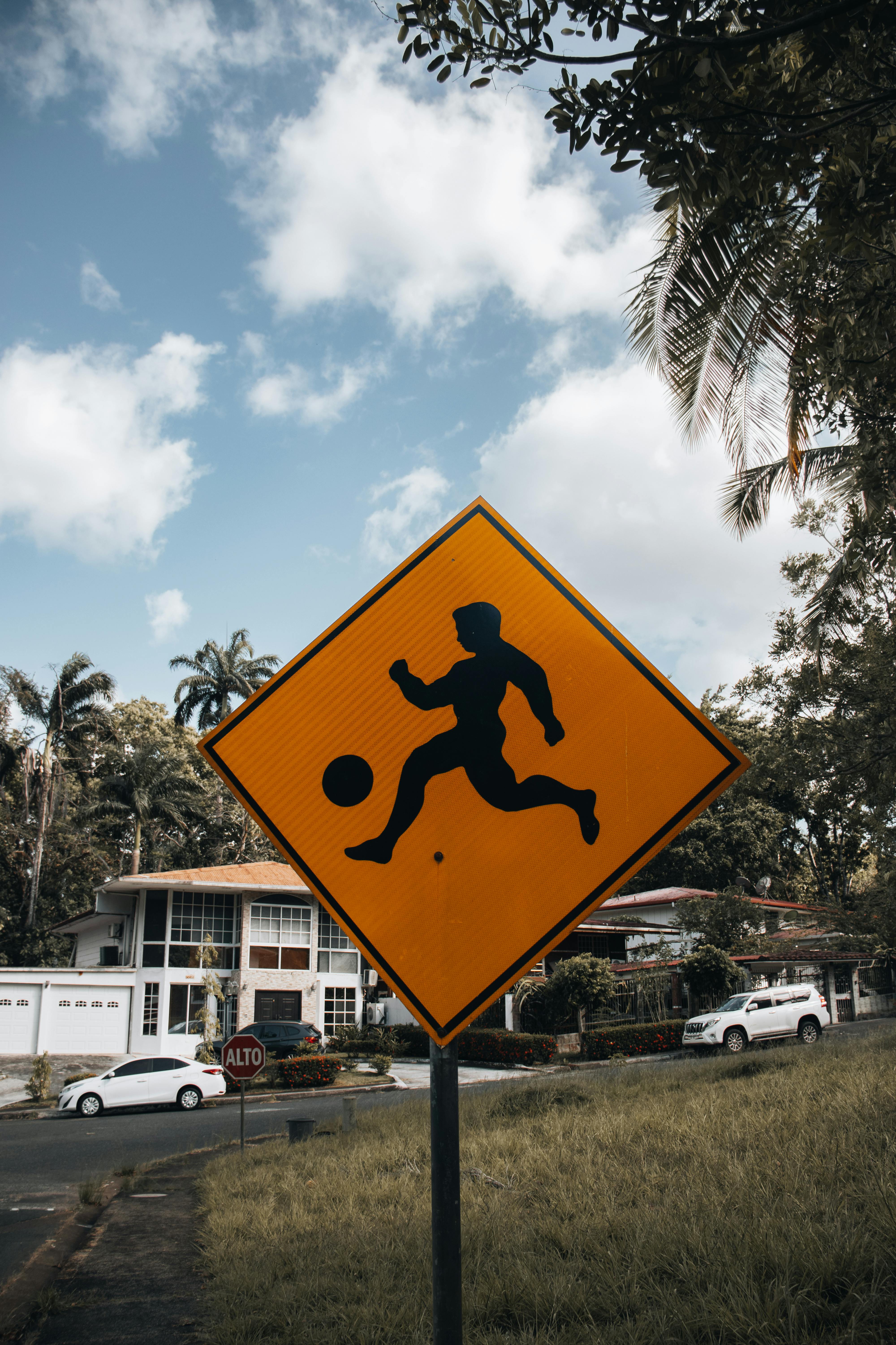 Man Playing Soccer on Road Sign · Free Stock Photo