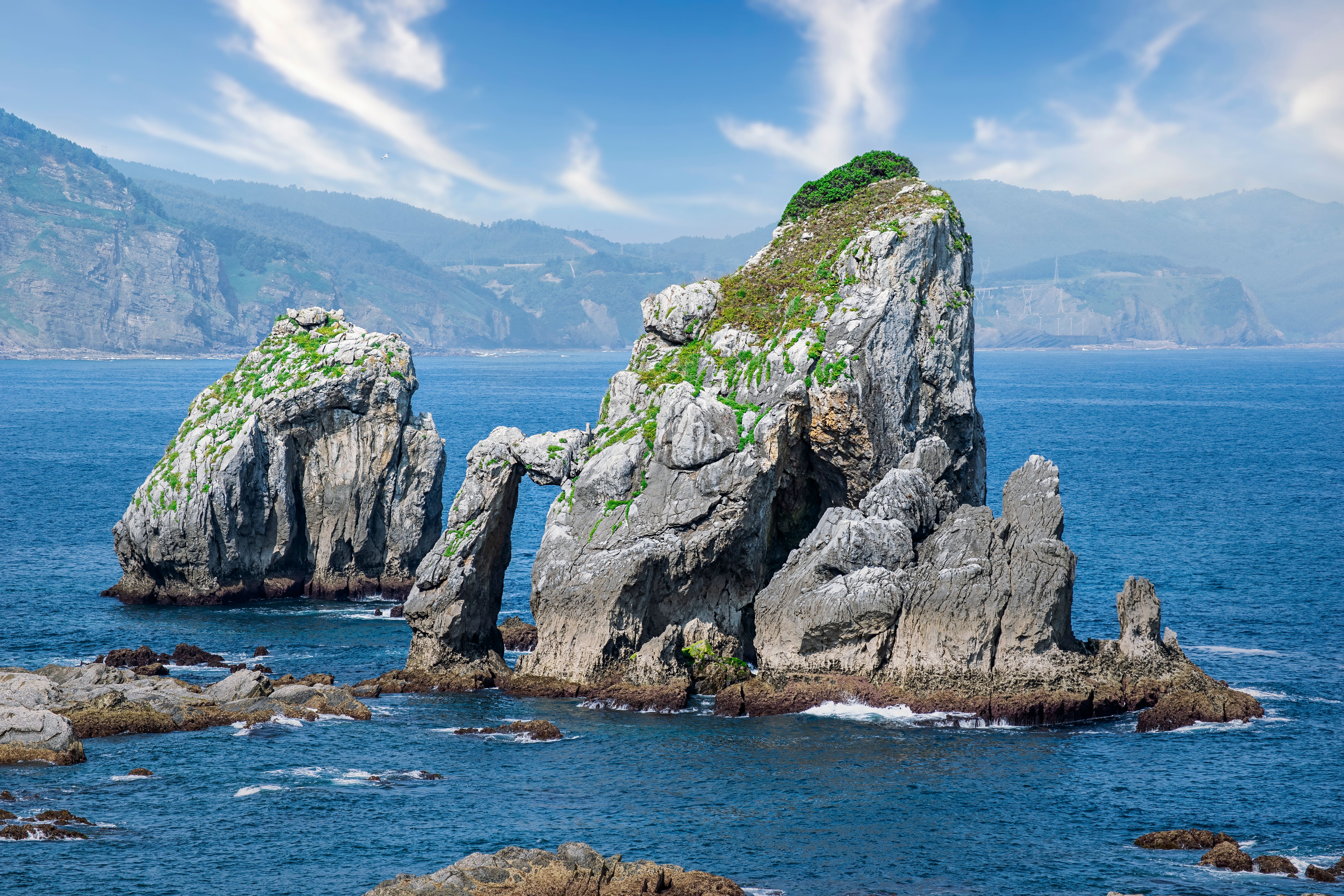 Two large rocks in the ocean with a body of water · Free Stock Photo