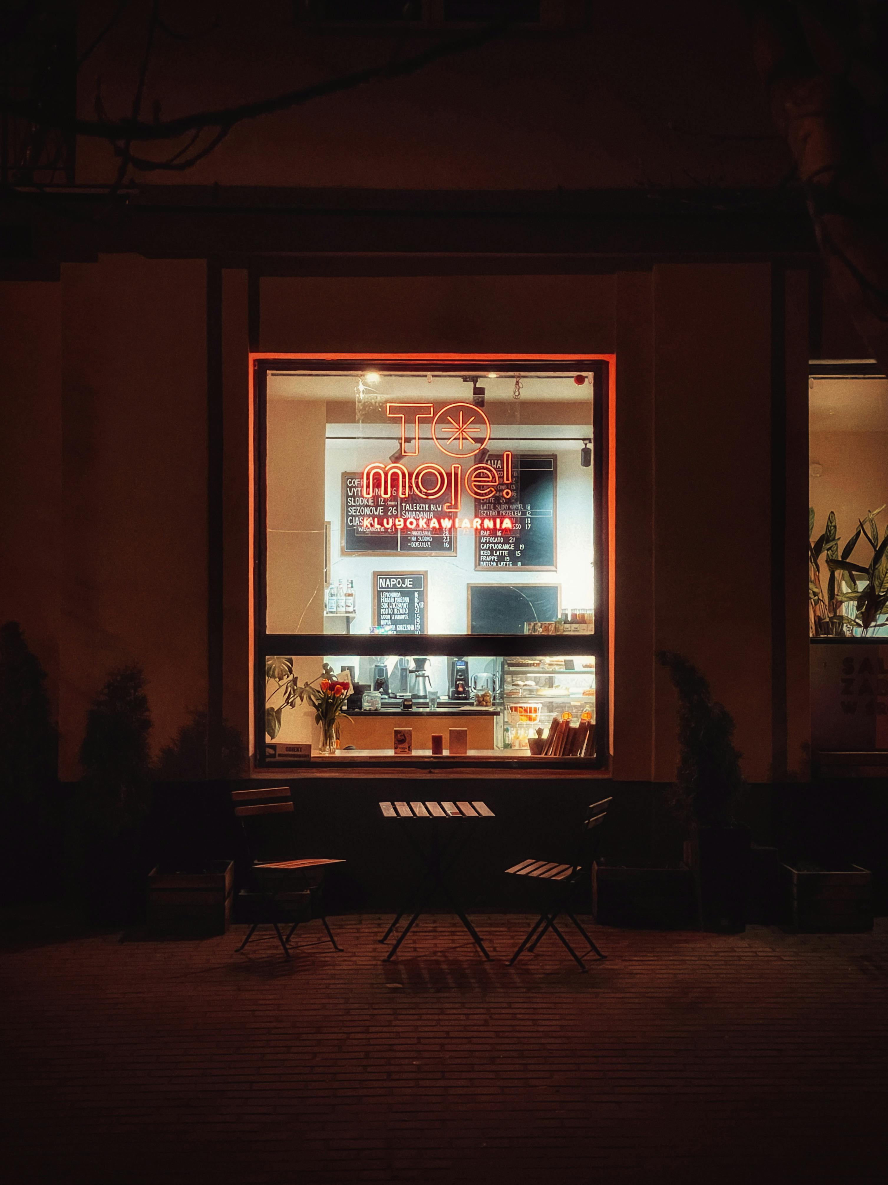 Table by the Window of a Cafe with a Neon Sign · Free Stock Photo