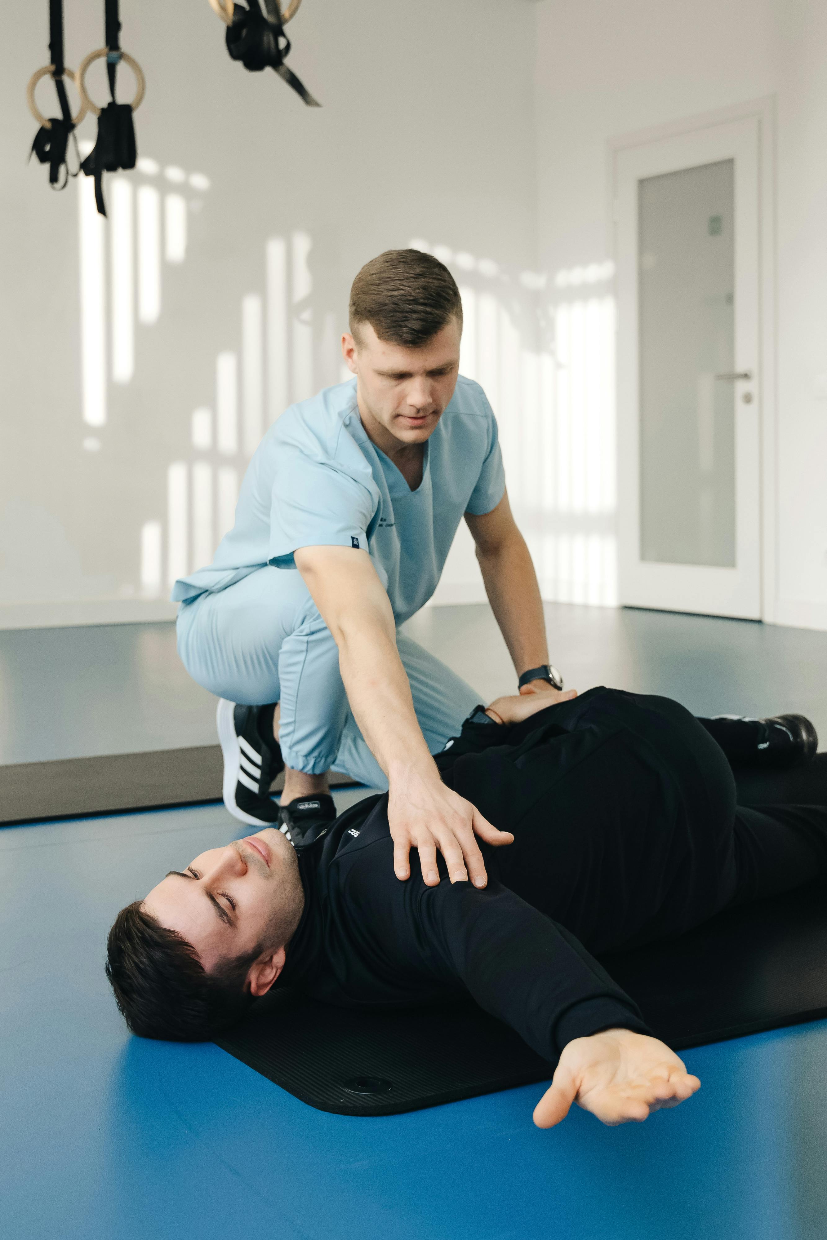 Physiotherapist Crouching over Exercising Patient · Free Stock Photo