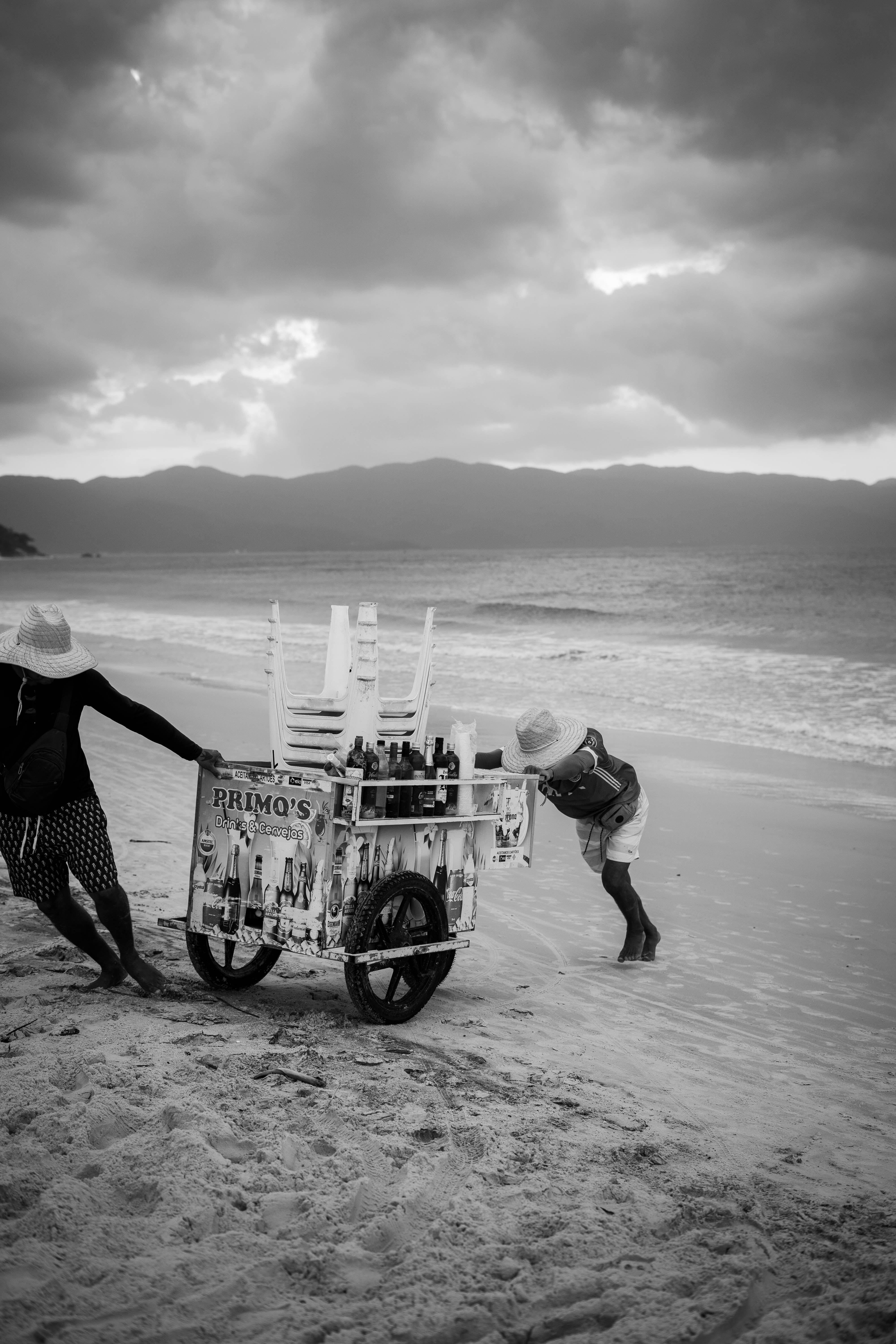 Two people pushing a cart on the beach · Free Stock Photo