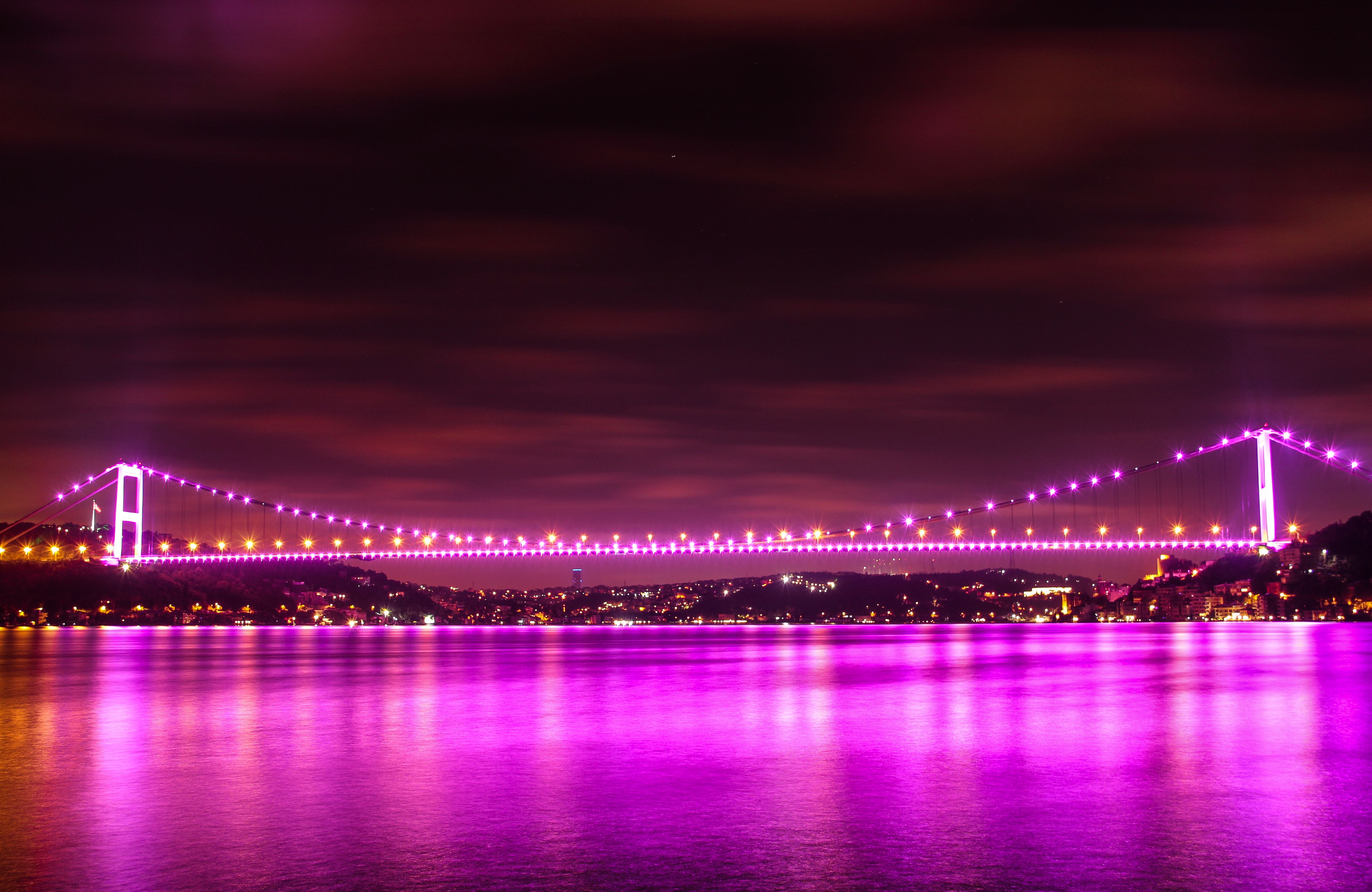 Pink Illuminated Suspension Bridge Reflecting in a River at Night ...