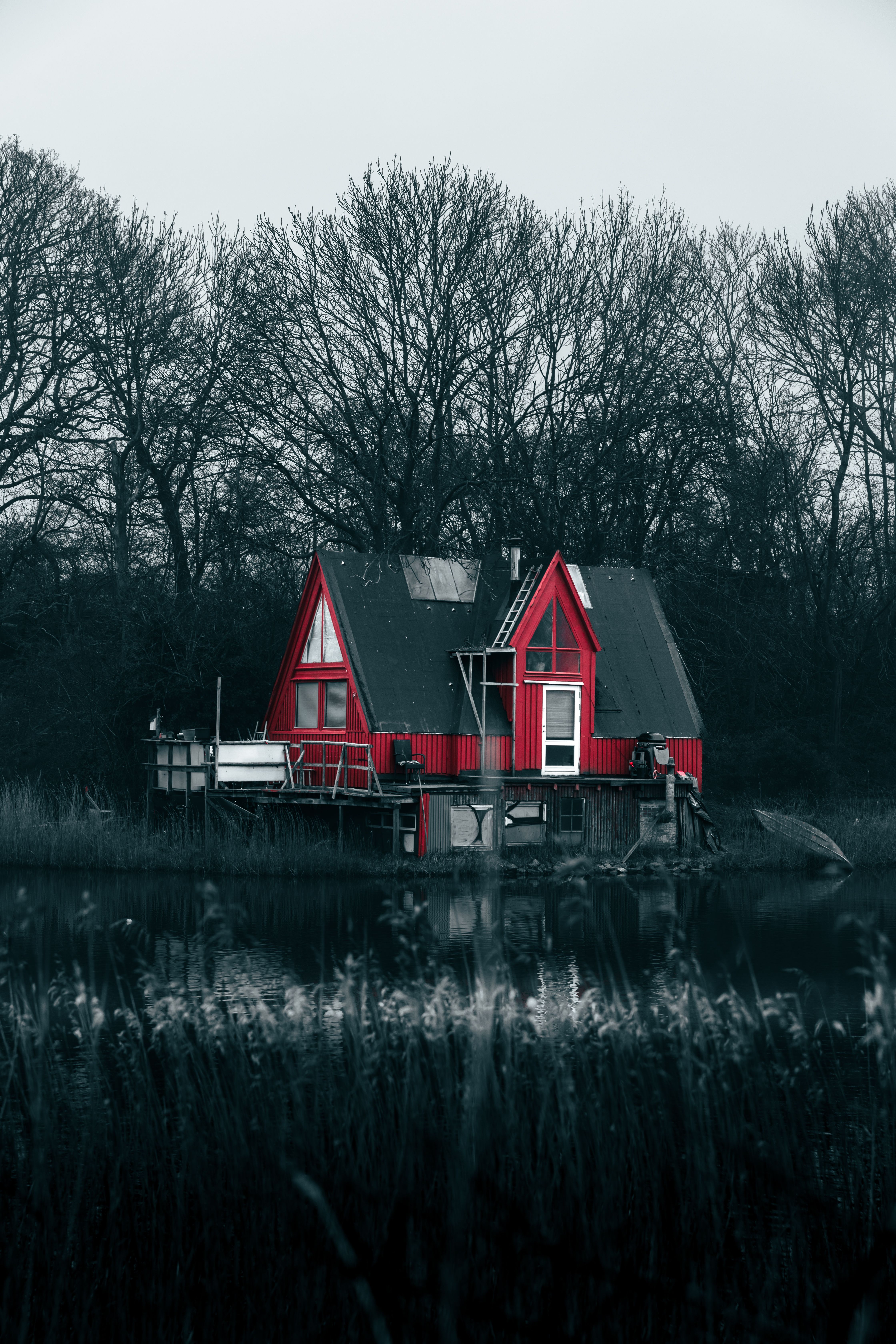 A red house on a lake with trees in the background · Free Stock Photo