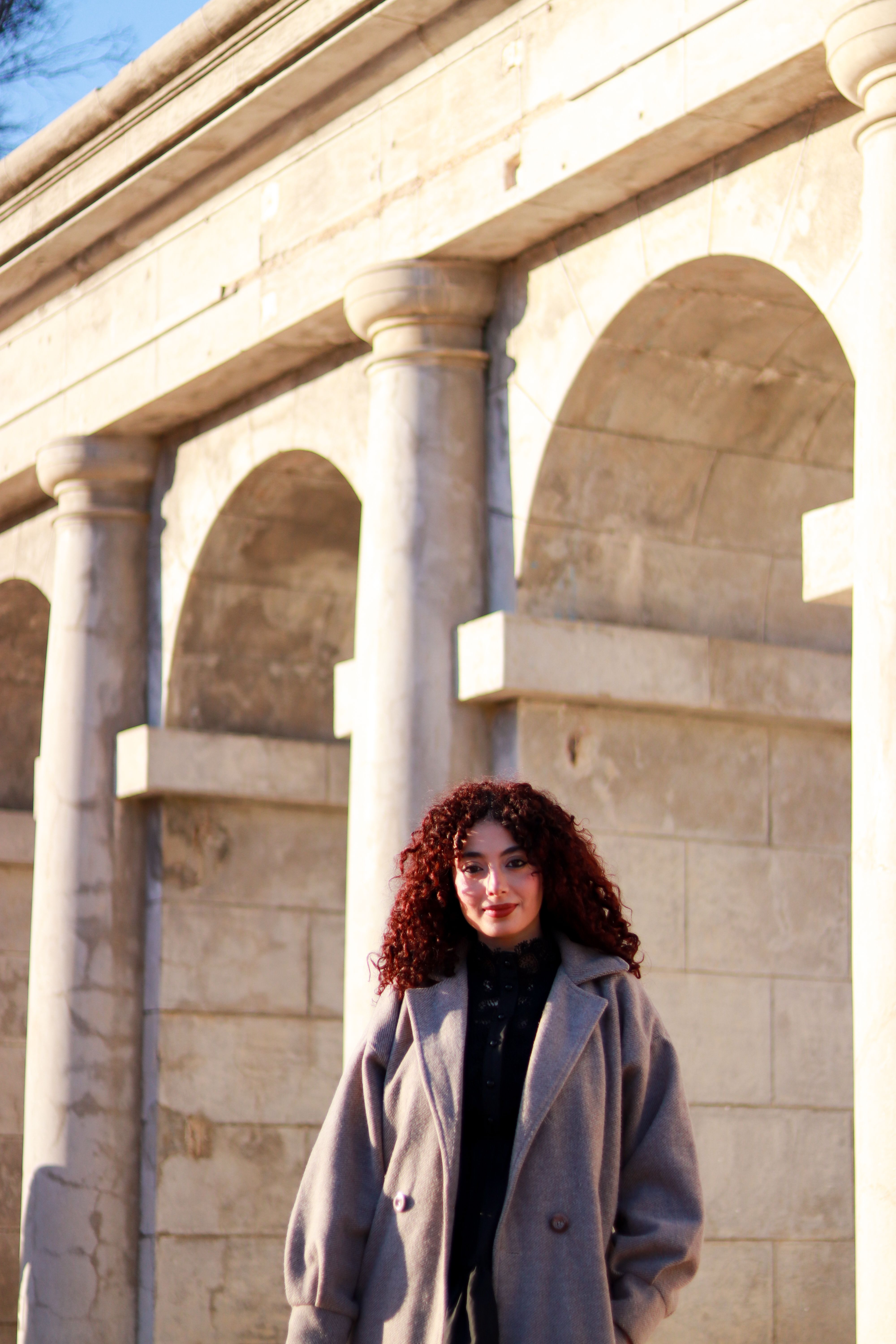 Woman in Front of an Arch Building in Sunlight · Free Stock Photo