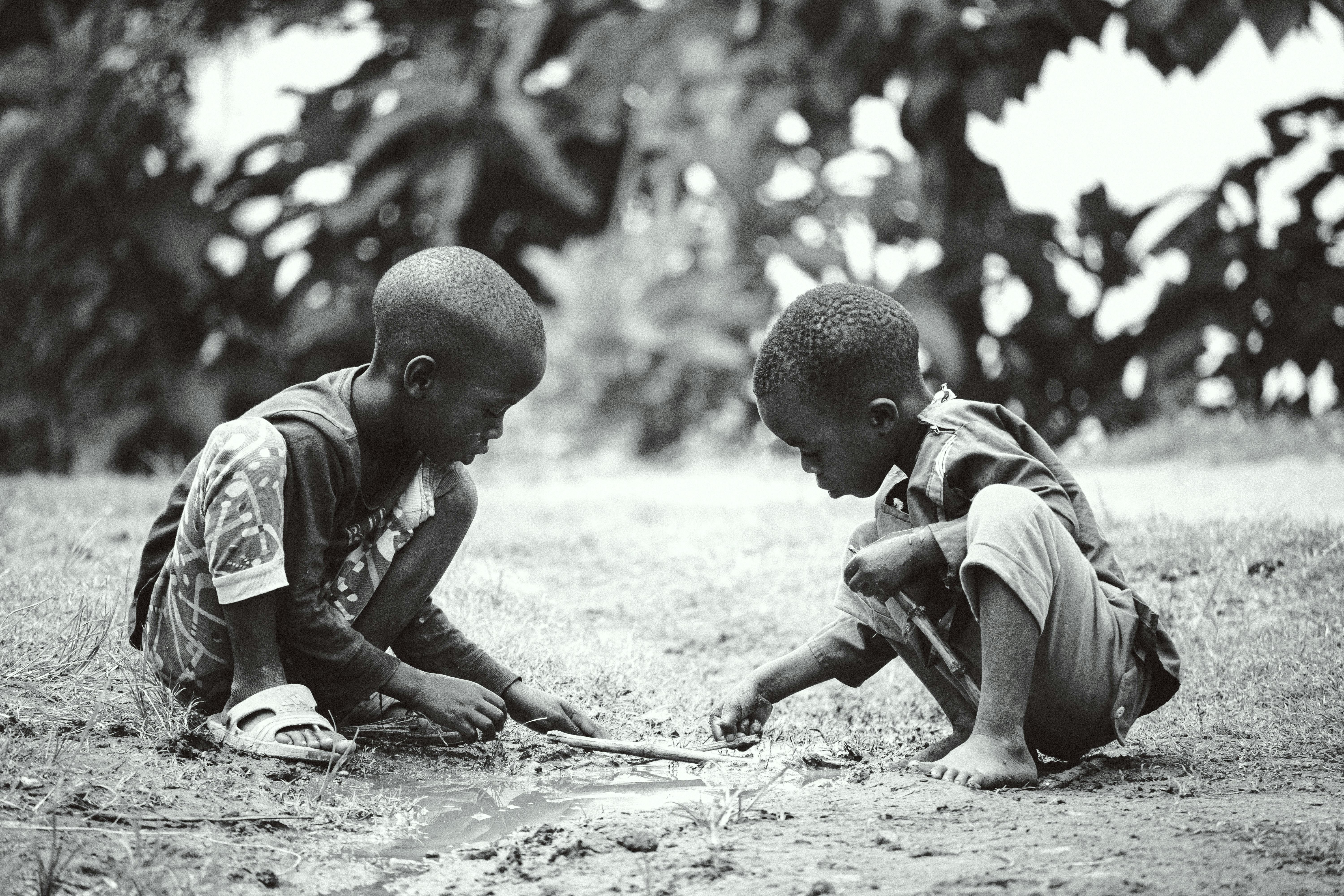 Two Boys Crouching Outdoors · Free Stock Photo