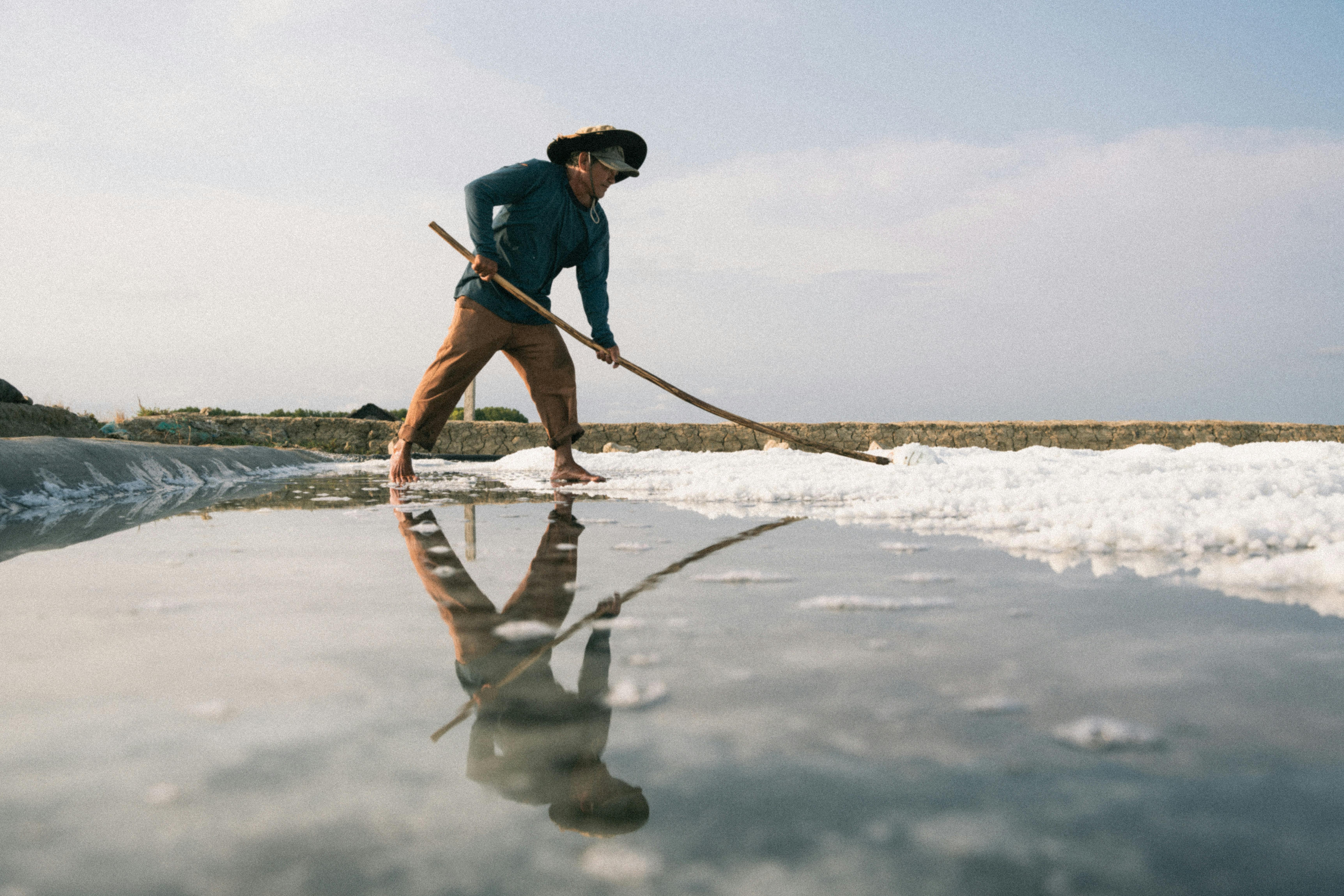 Man Pushing Ice with a Stick Standing on a Frozen River · Free Stock Photo