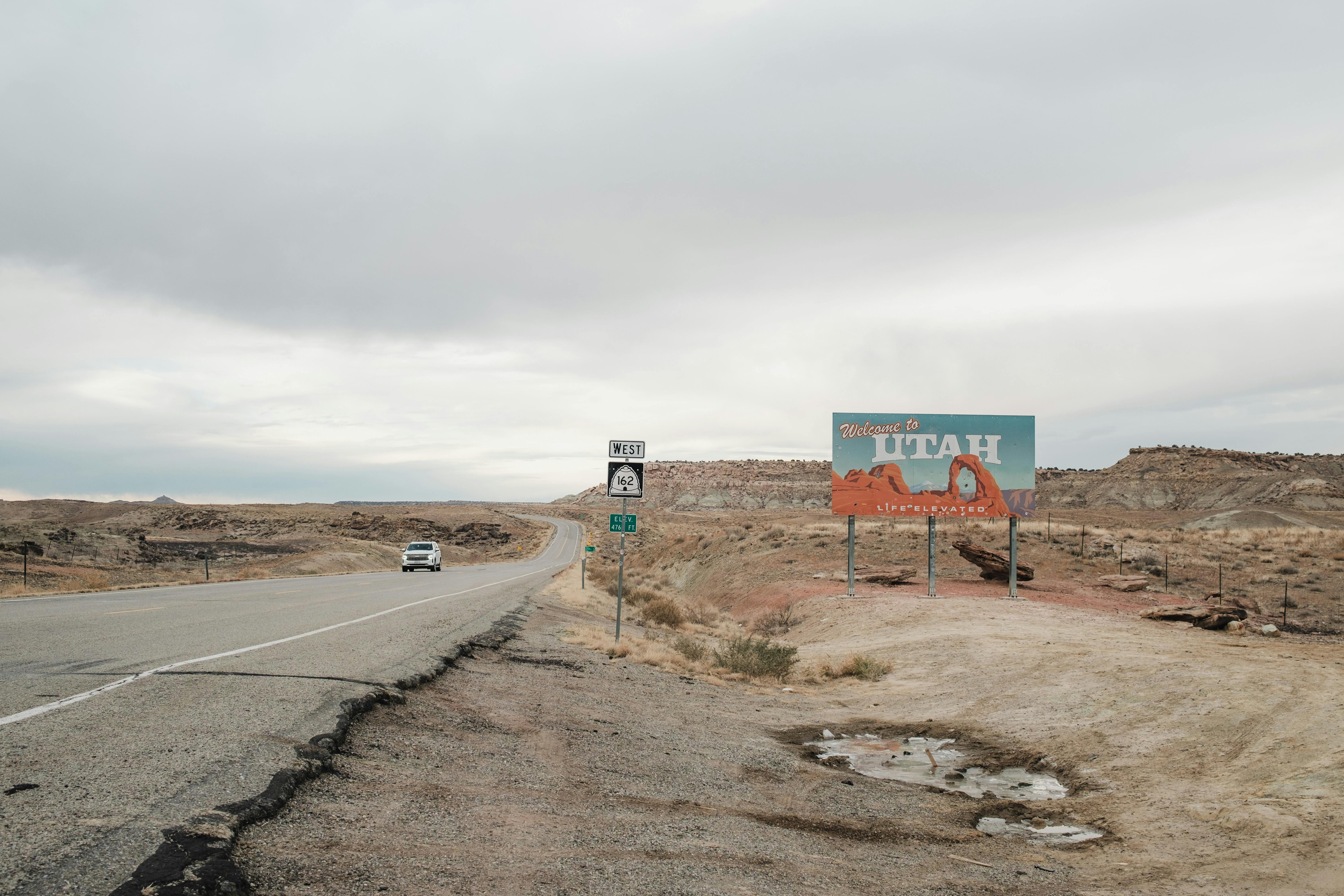 Brown Road Sign on Pavement Near Mountain · Free Stock Photo
