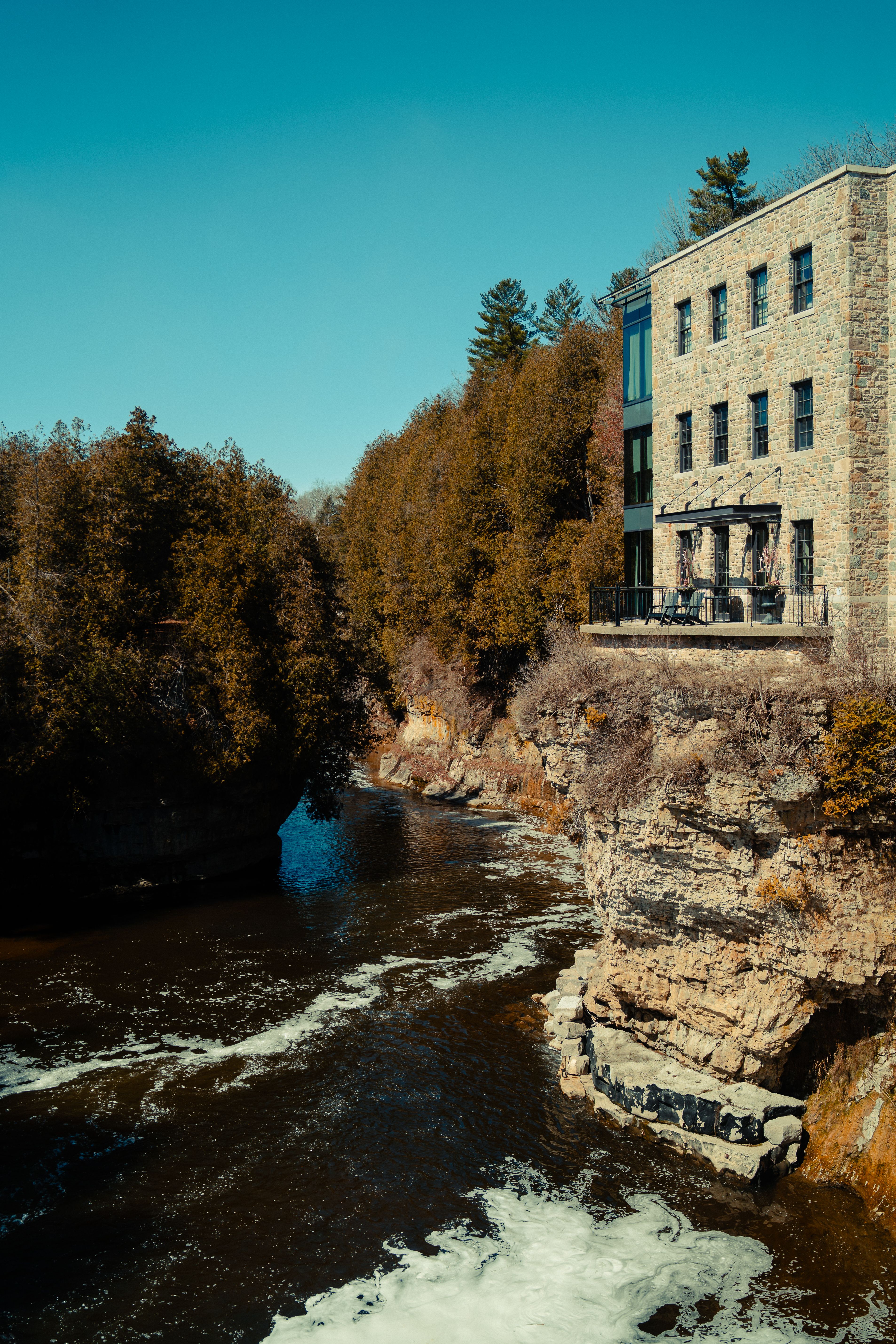 A building sits on top of a cliff next to a river · Free Stock Photo