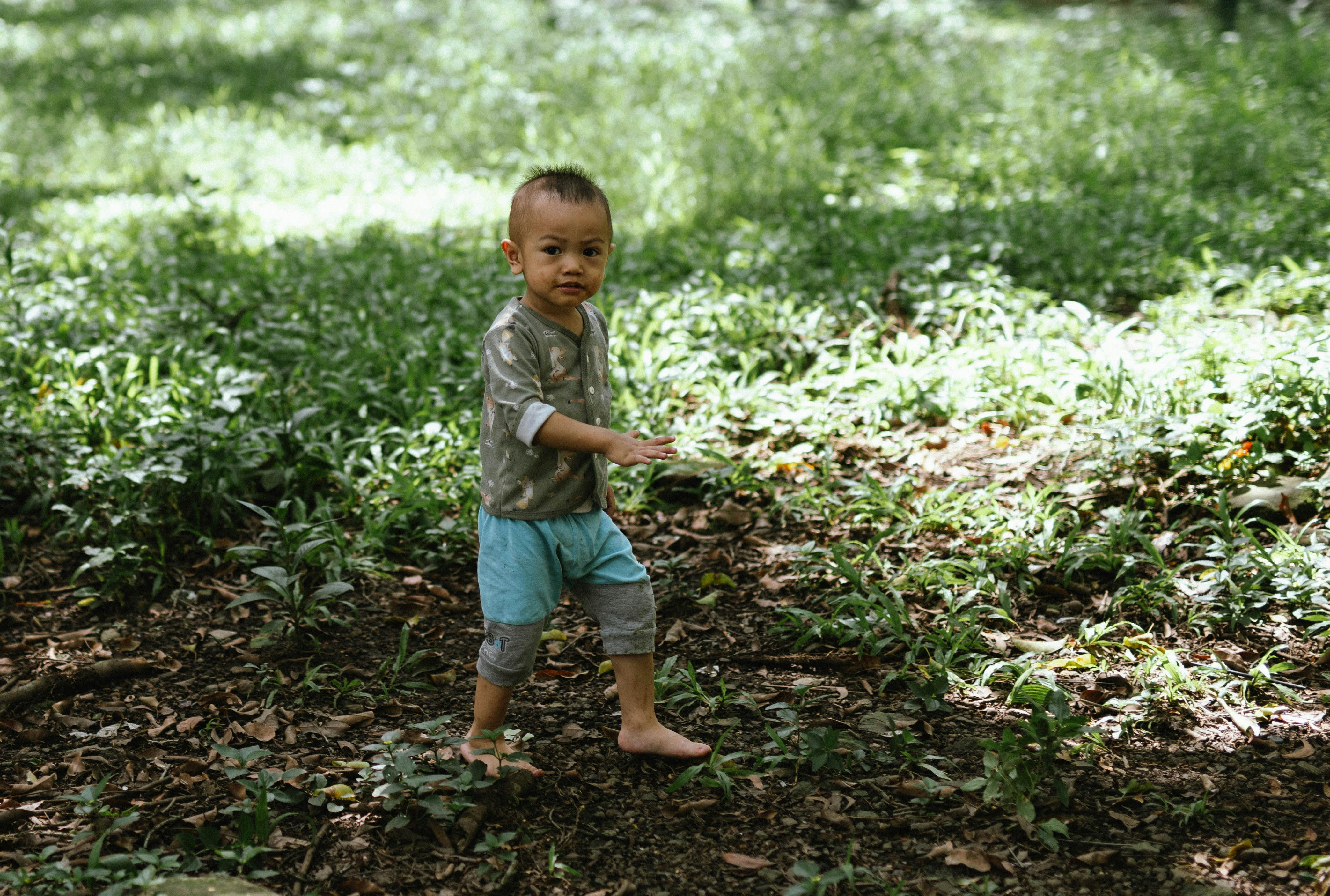 A toddler is playing in the woods · Free Stock Photo