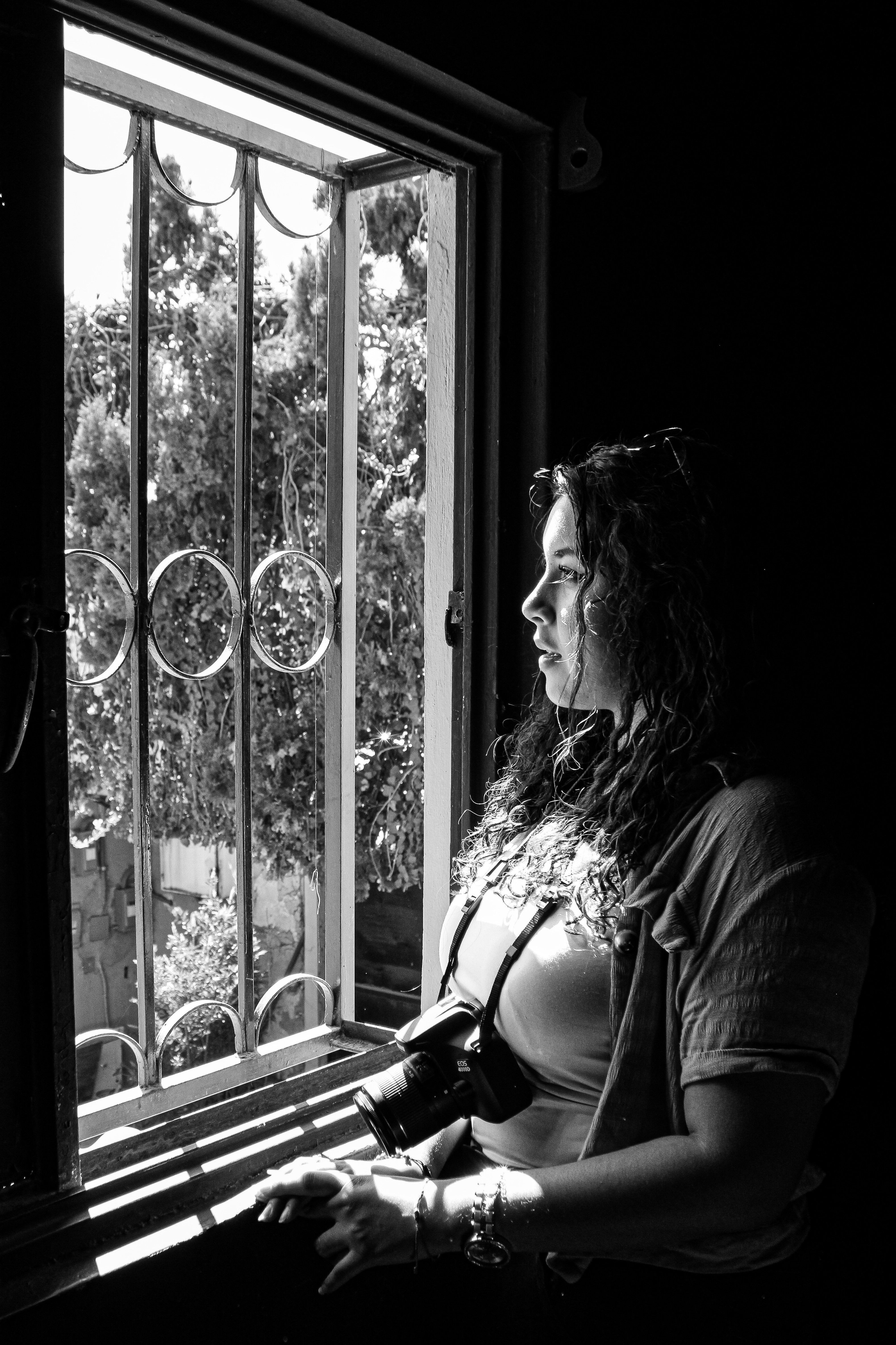 Woman with a Camera Looking out the Window · Free Stock Photo