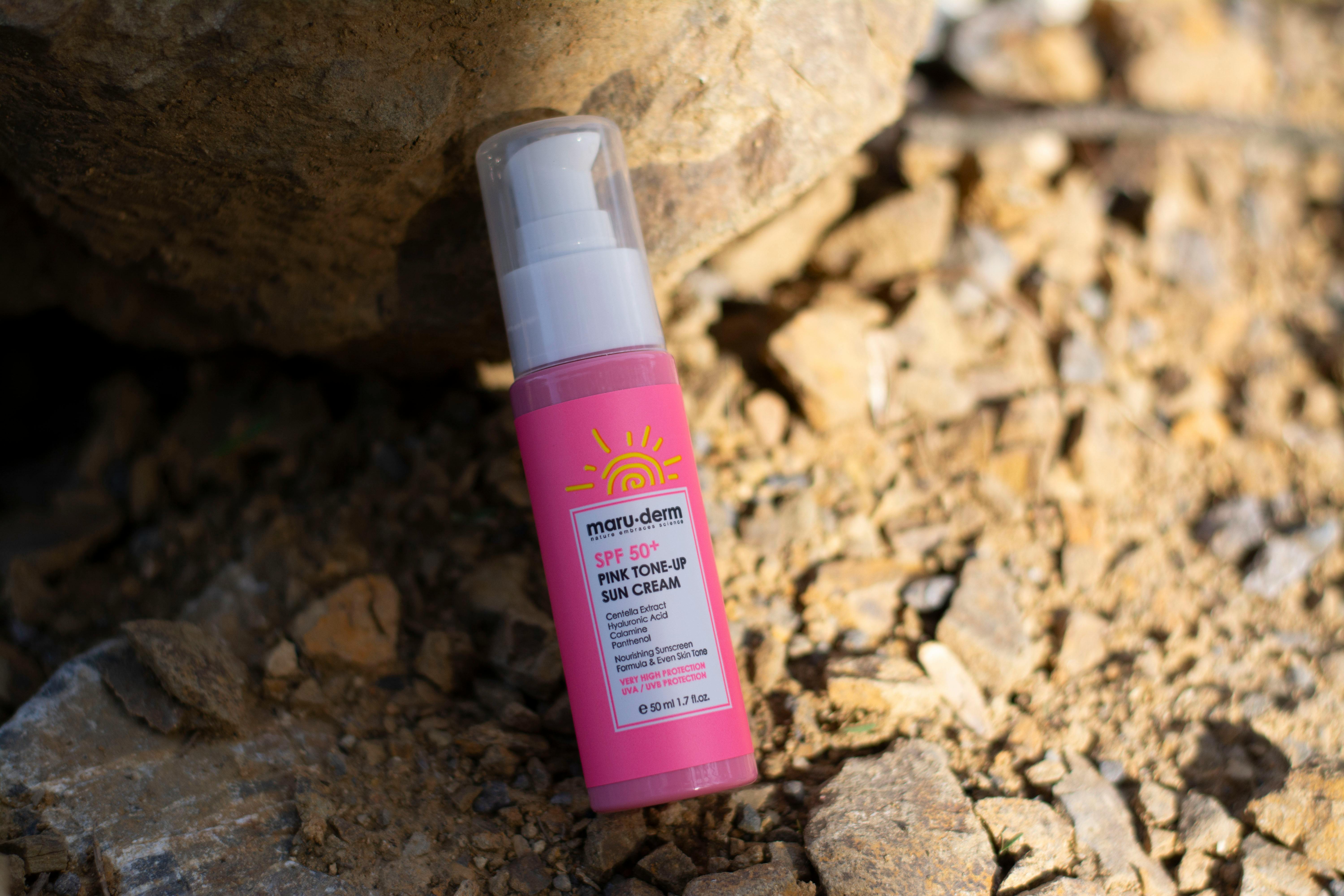 SPF 50 Sun Cream in Pink Bottle on Rocks · Free Stock Photo