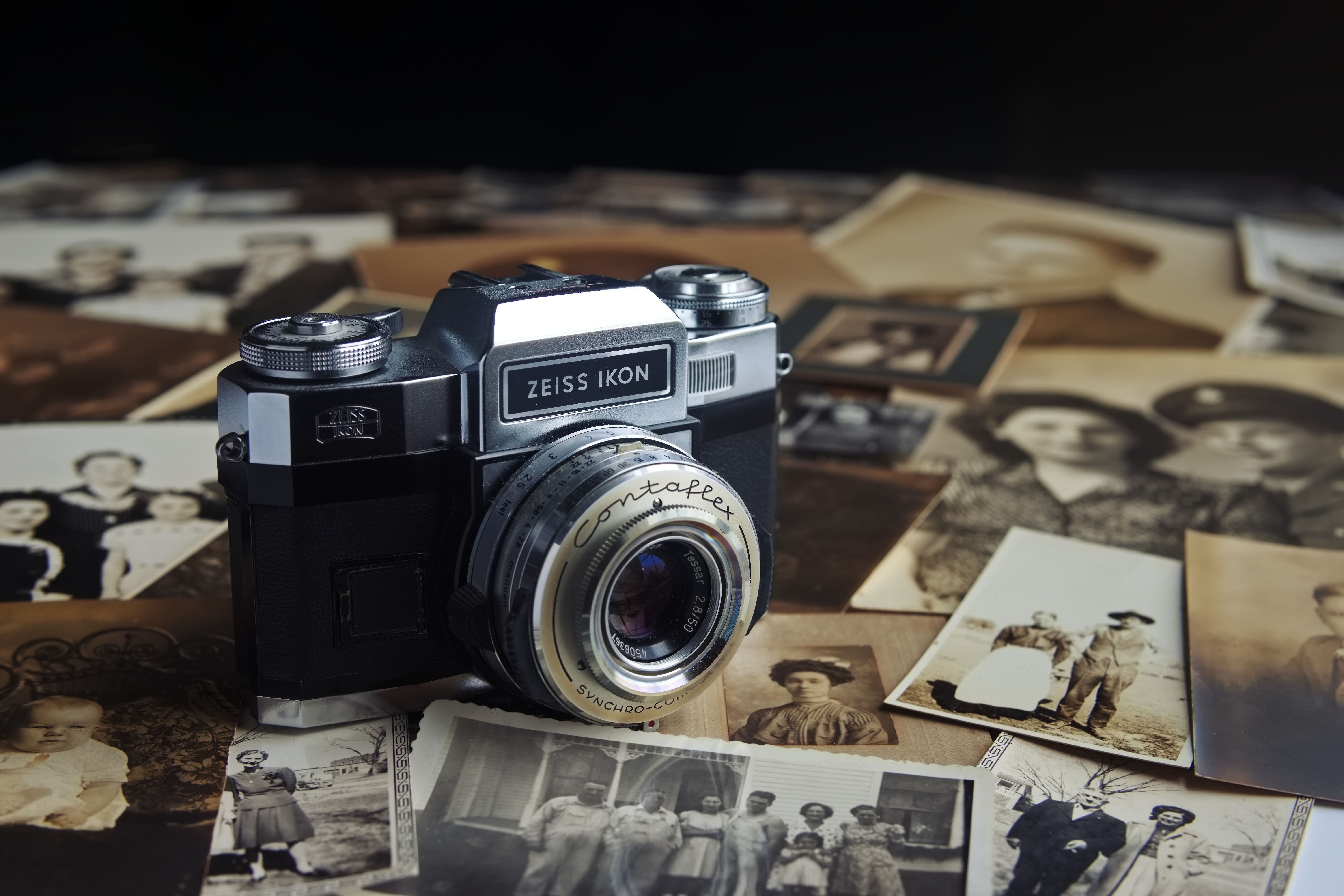 An old camera sitting on top of a pile of old photos · Free Stock Photo