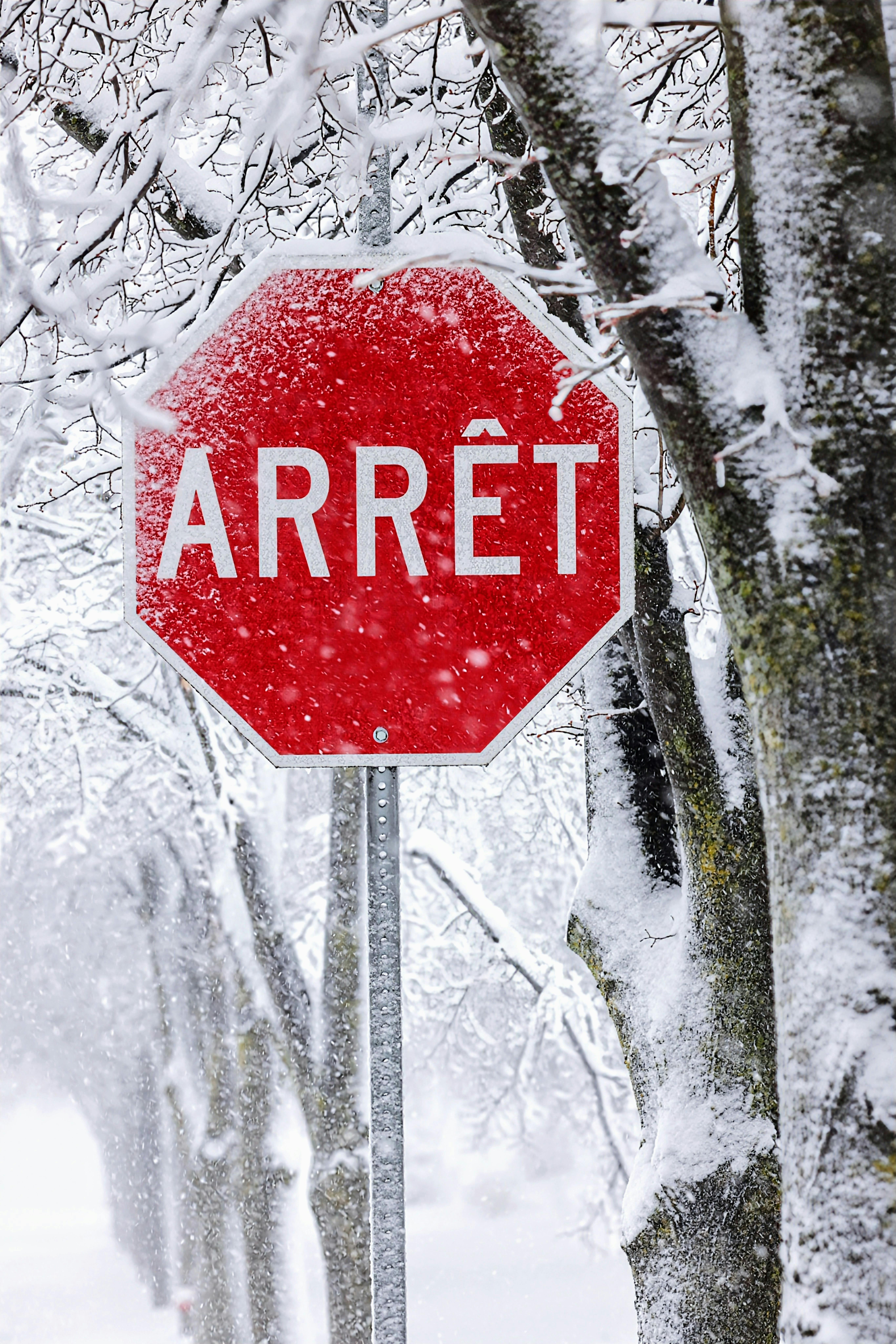 A stop sign with the word arret on it in the snow · Free Stock Photo