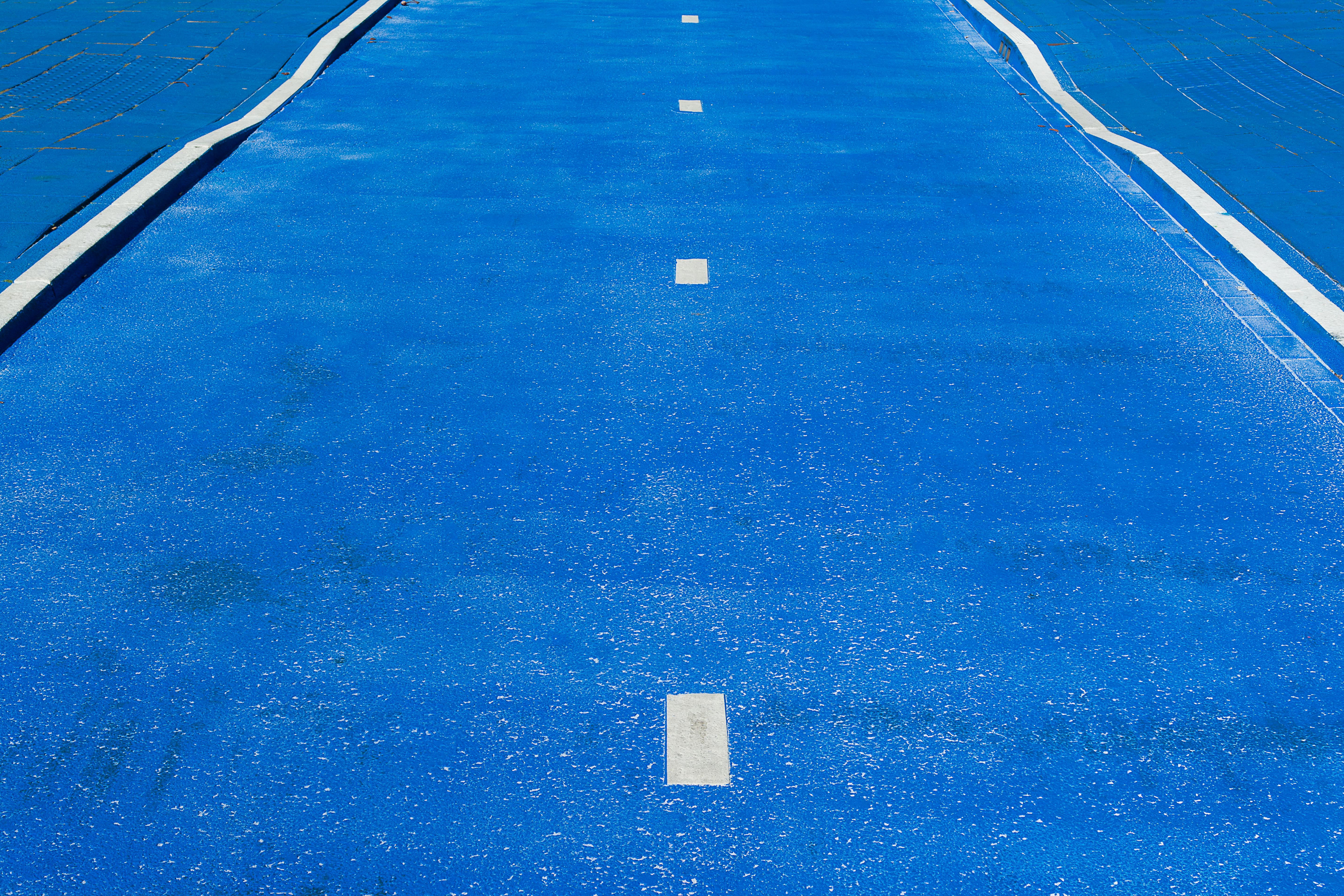 A blue track with white lines on it · Free Stock Photo