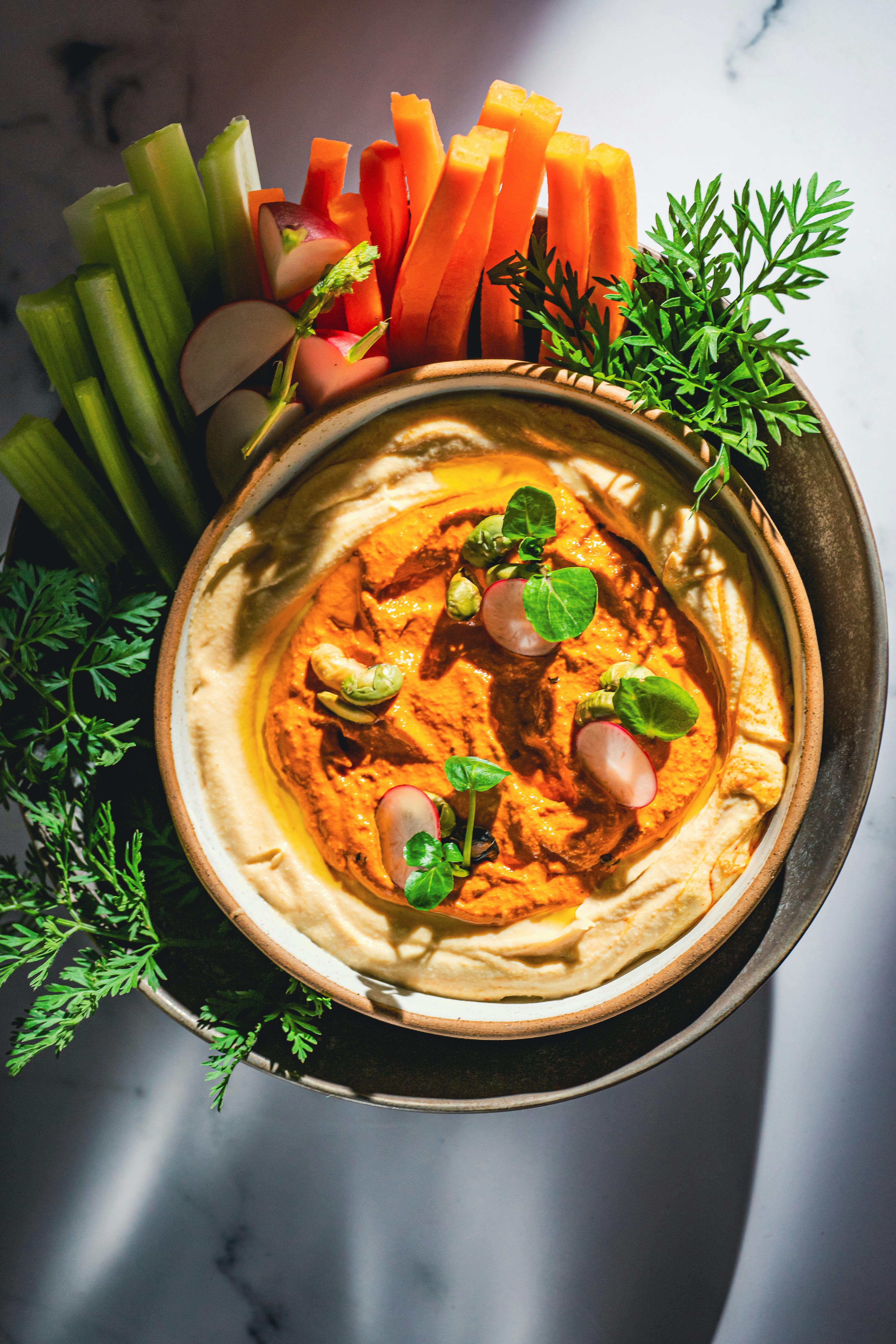 A bowl of hummus with carrots and celery · Free Stock Photo