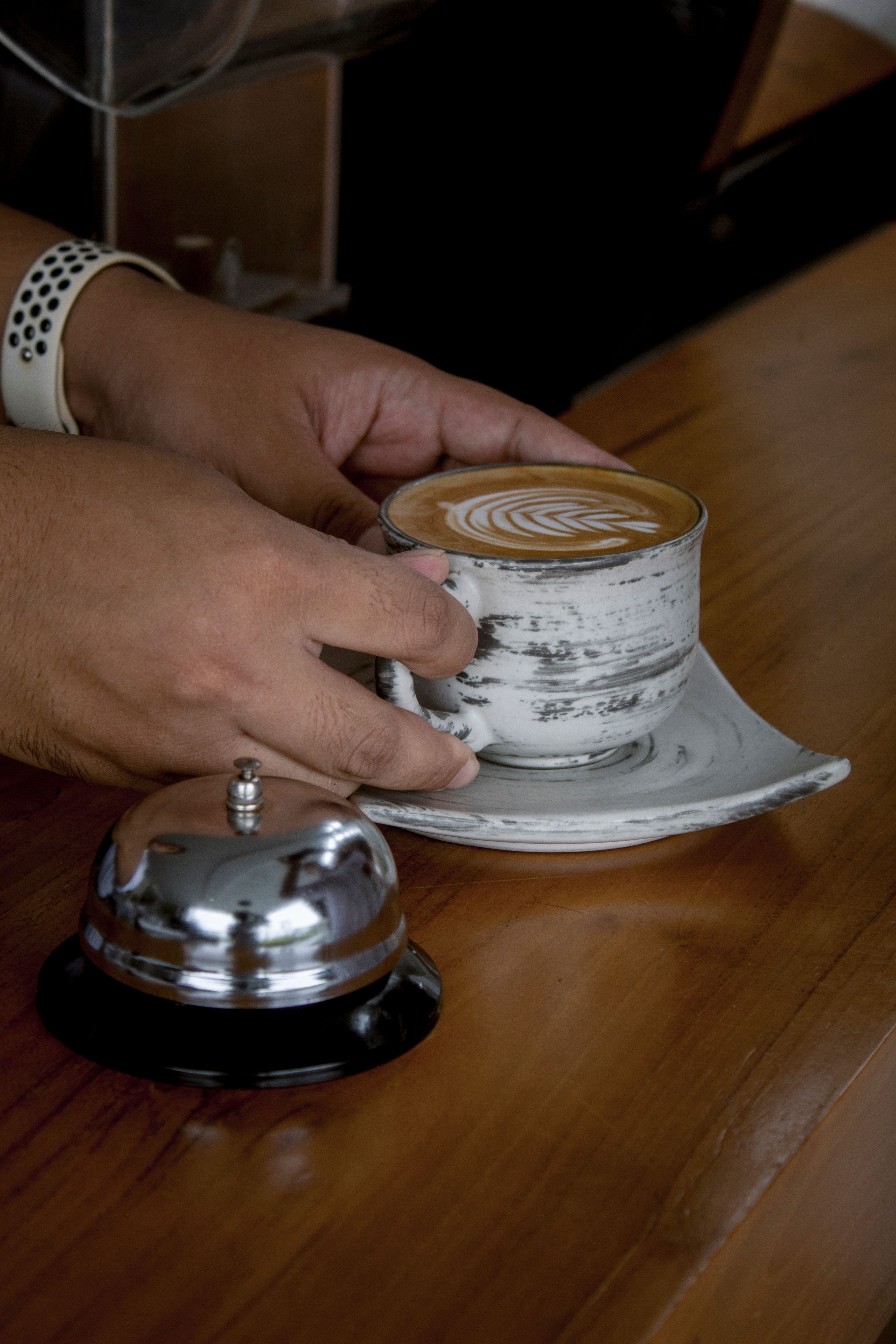 A person holding a coffee cup and a bell · Free Stock Photo