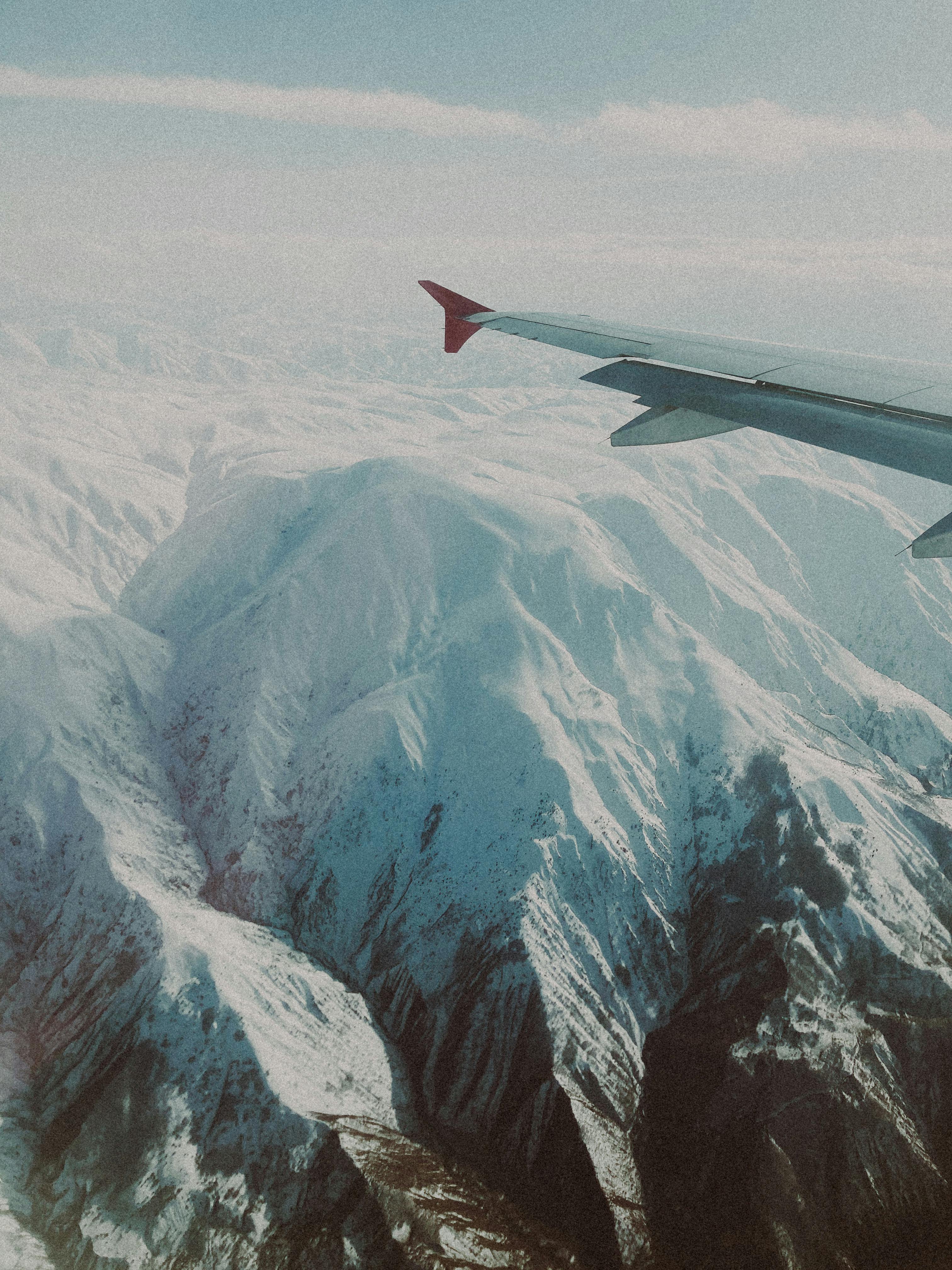 Wing of Airplane Flying over Mountains in Snow · Free Stock Photo