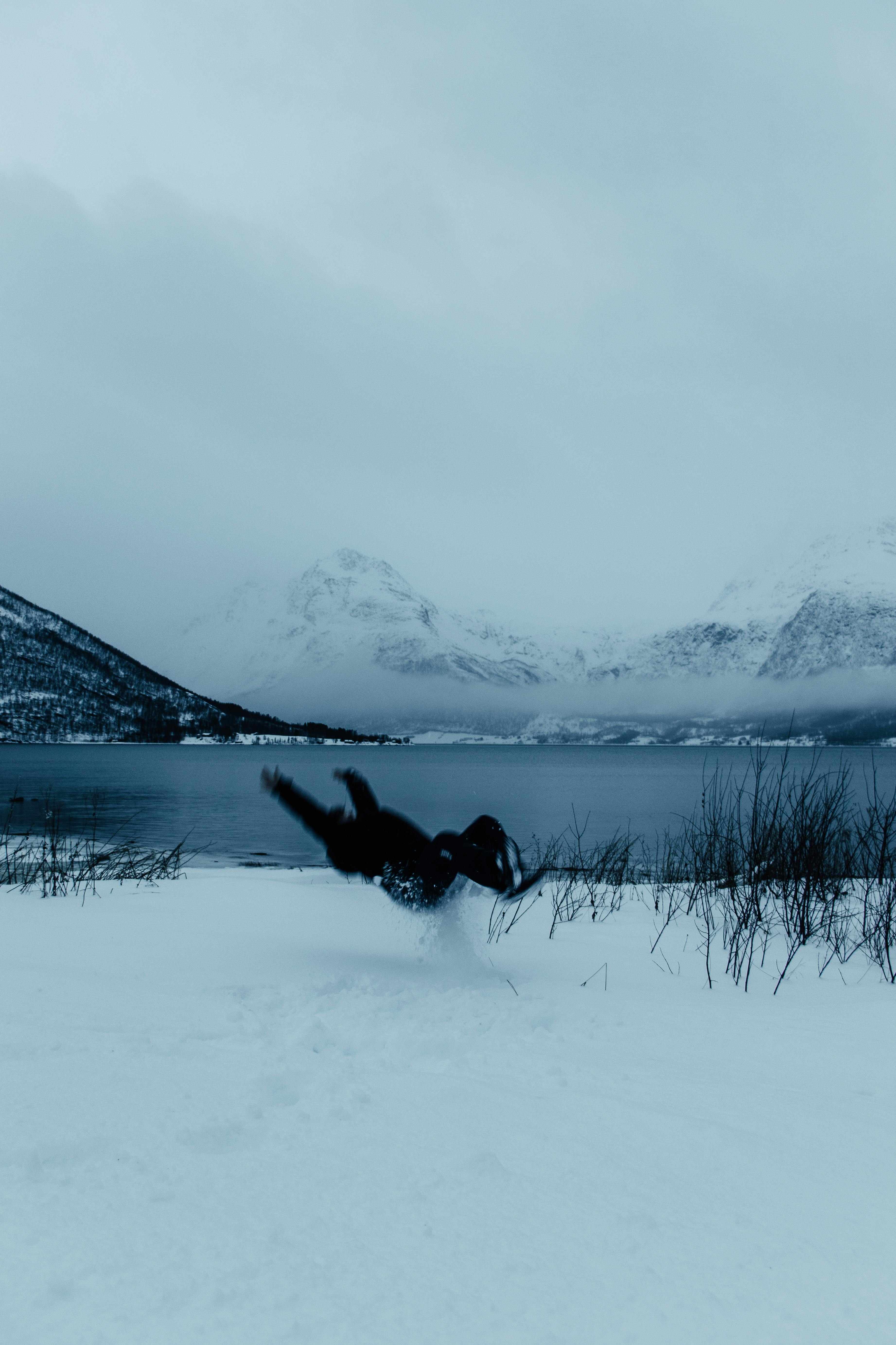 Person Jumping in Snow near Lake in Winter · Free Stock Photo
