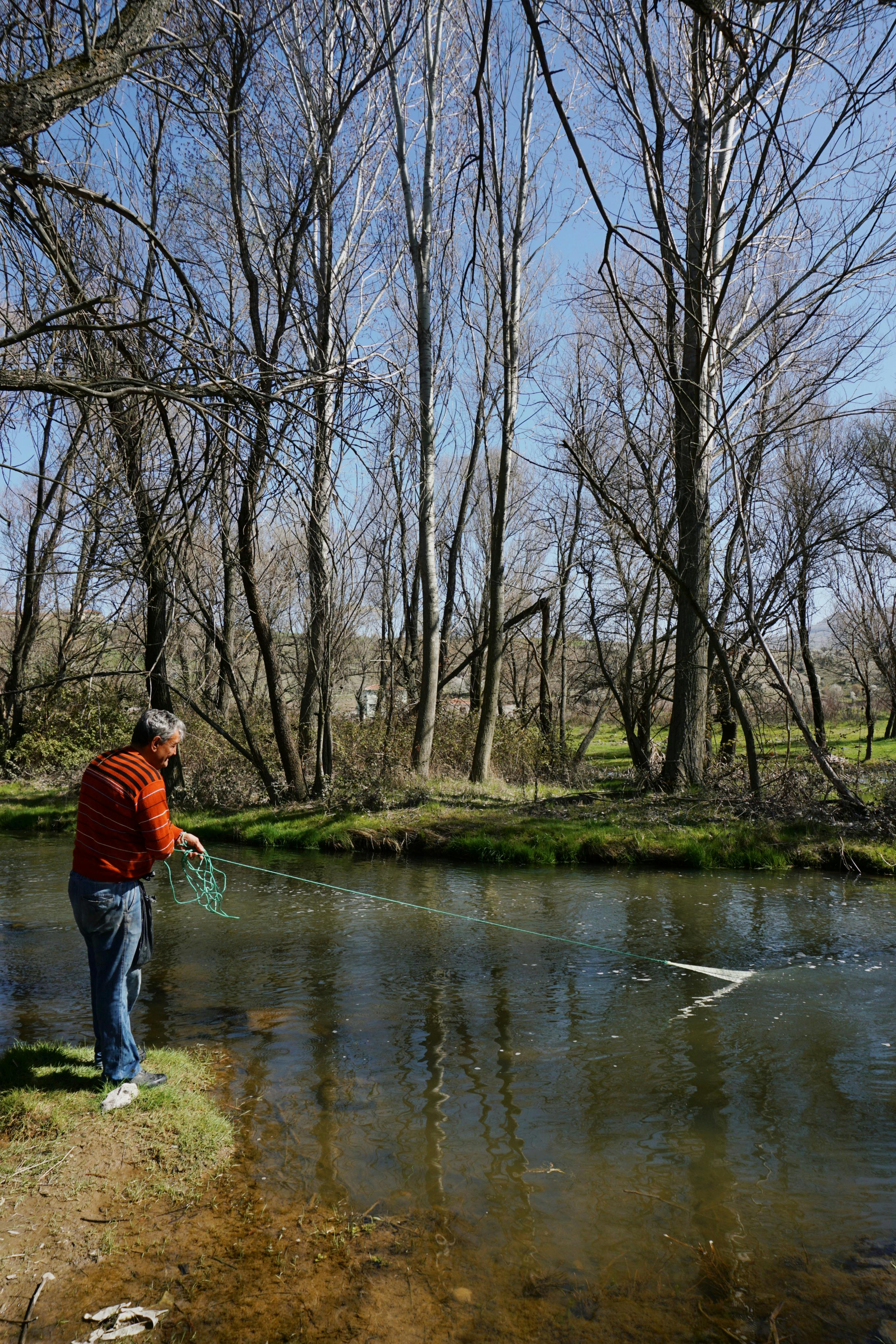 Man Pulling Fishing Net from River · Free Stock Photo