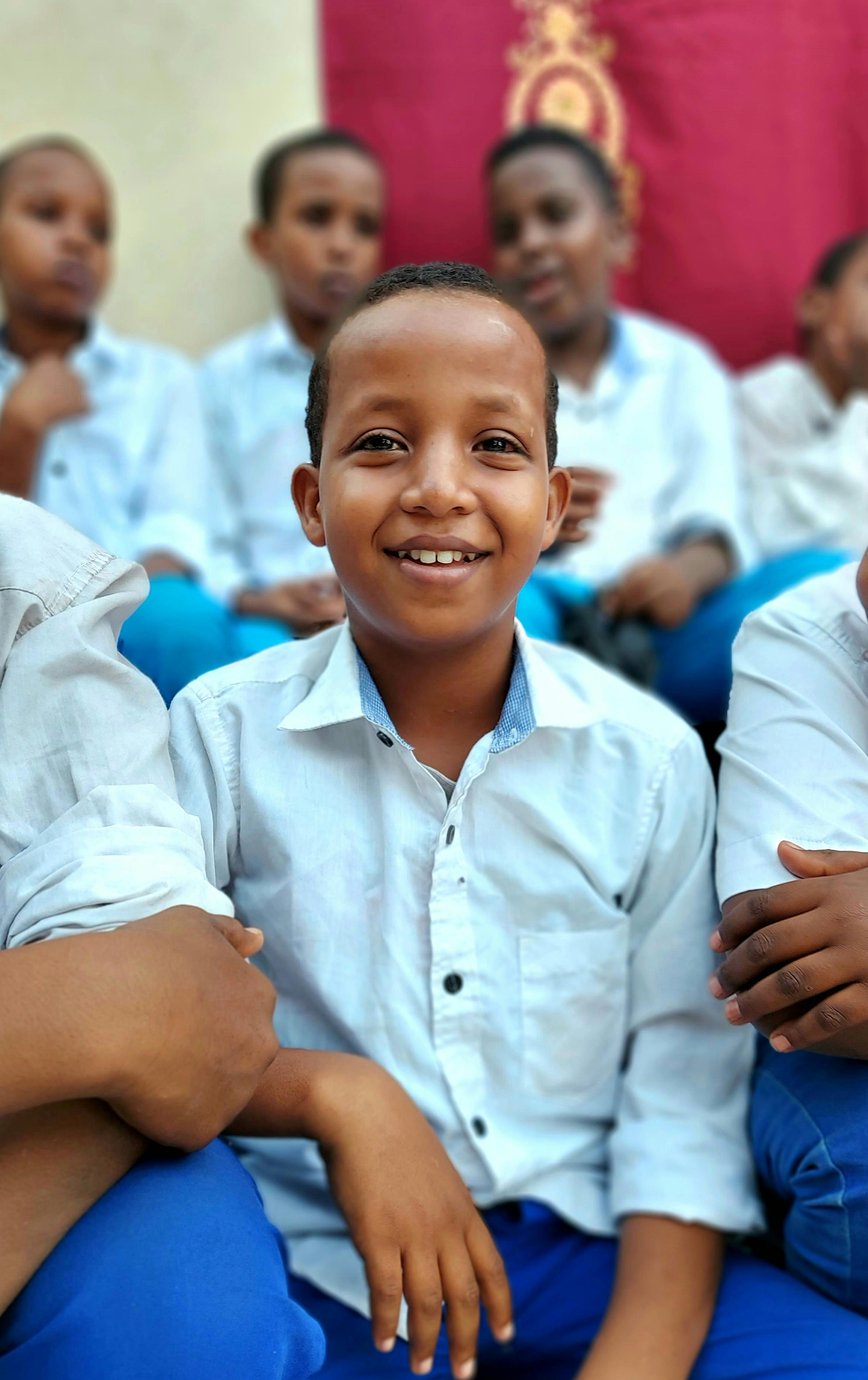 A group of children sitting together smiling · Free Stock Photo