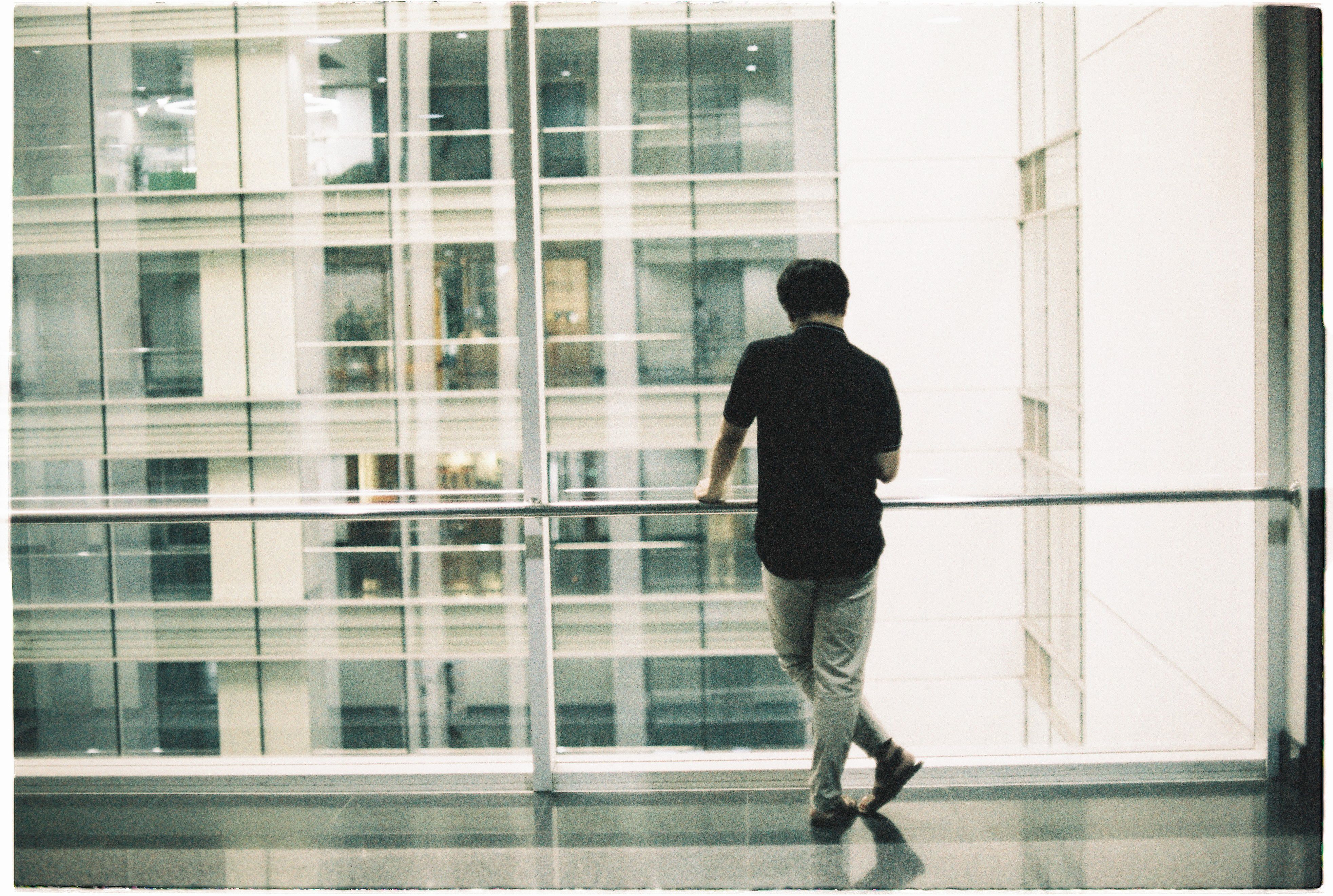 Man Standing by Large Window in Modern Building · Free Stock Photo