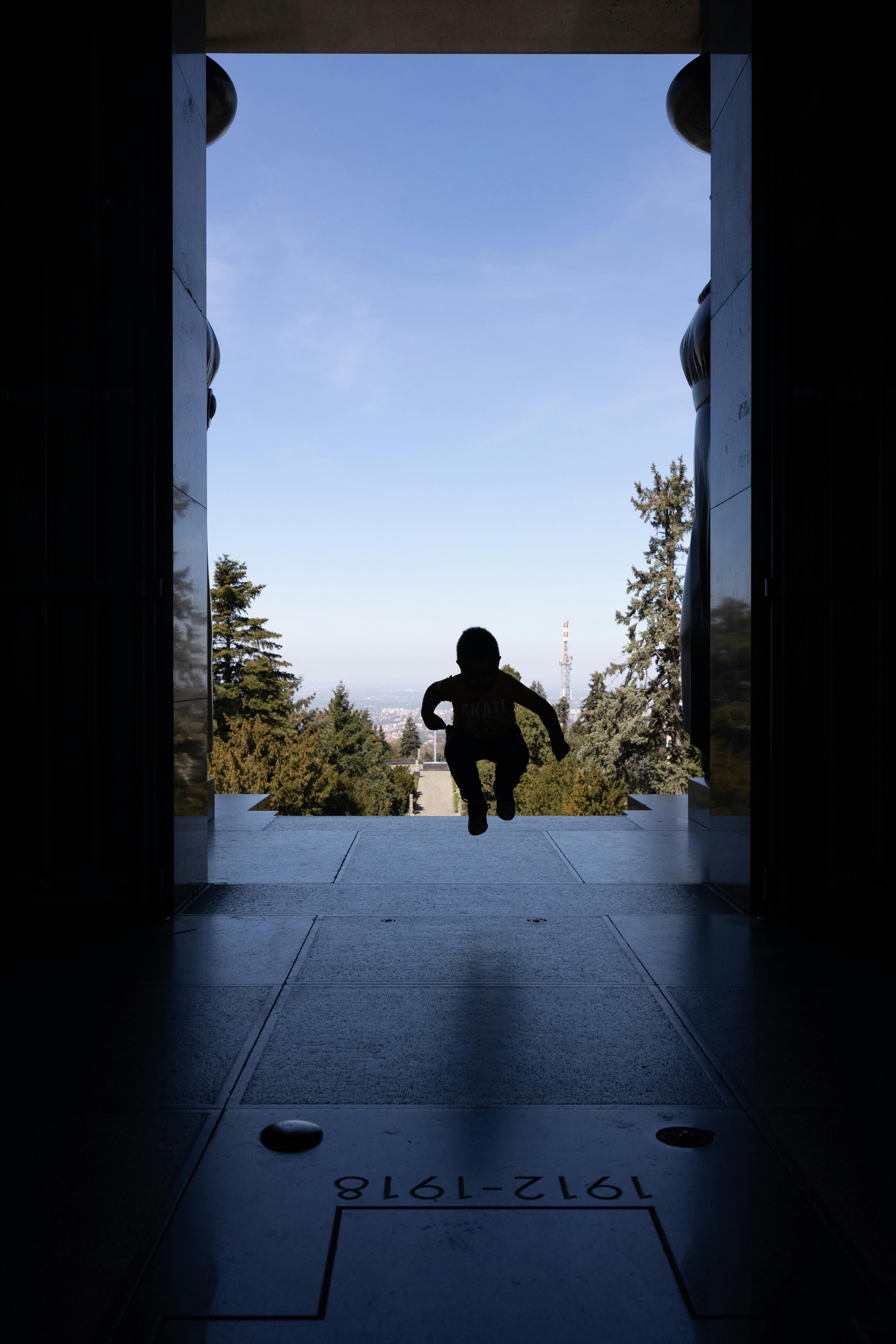 Child Jumping in Gate to Dark Building · Free Stock Photo