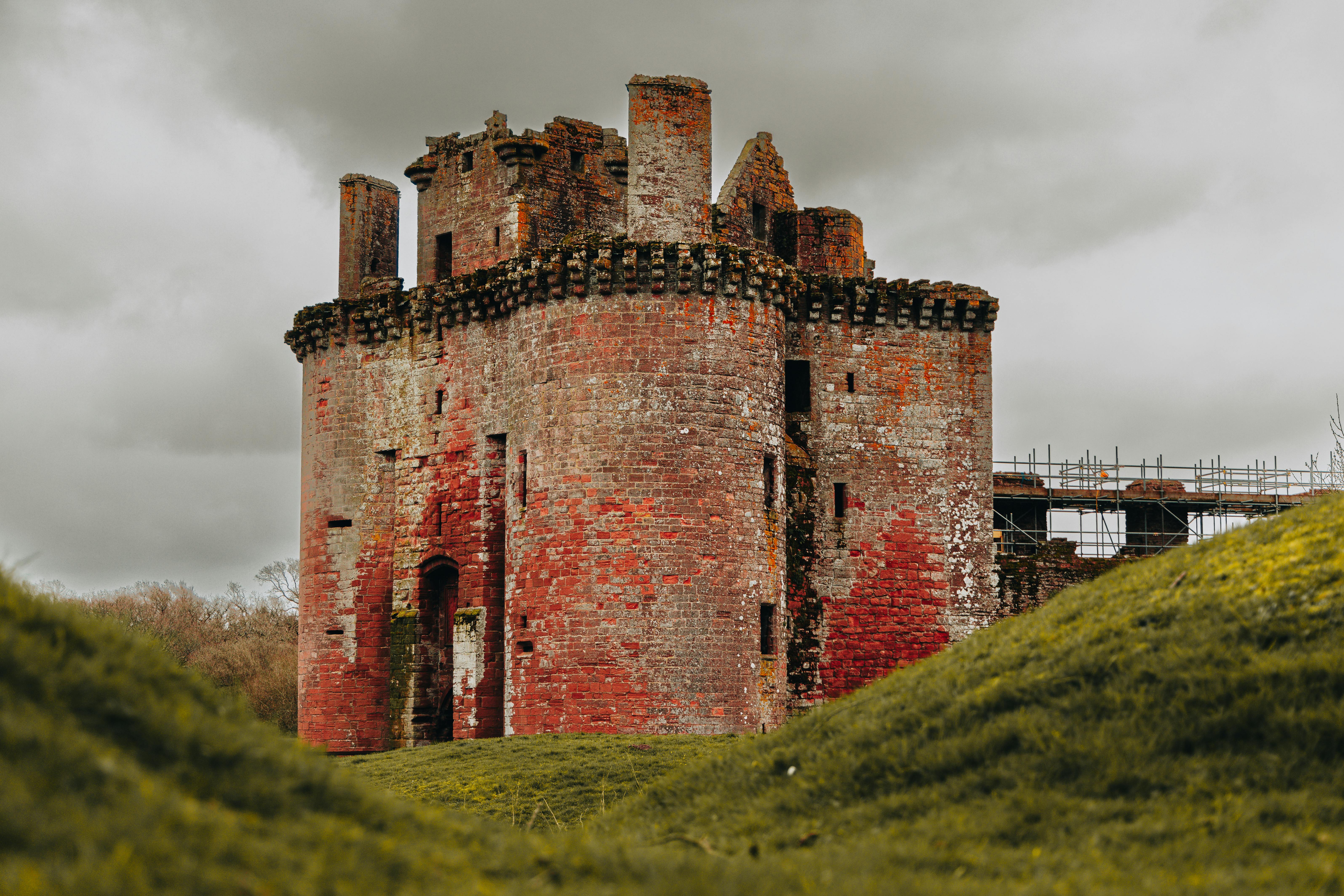 A red brick castle sits on top of a green hill · Free Stock Photo