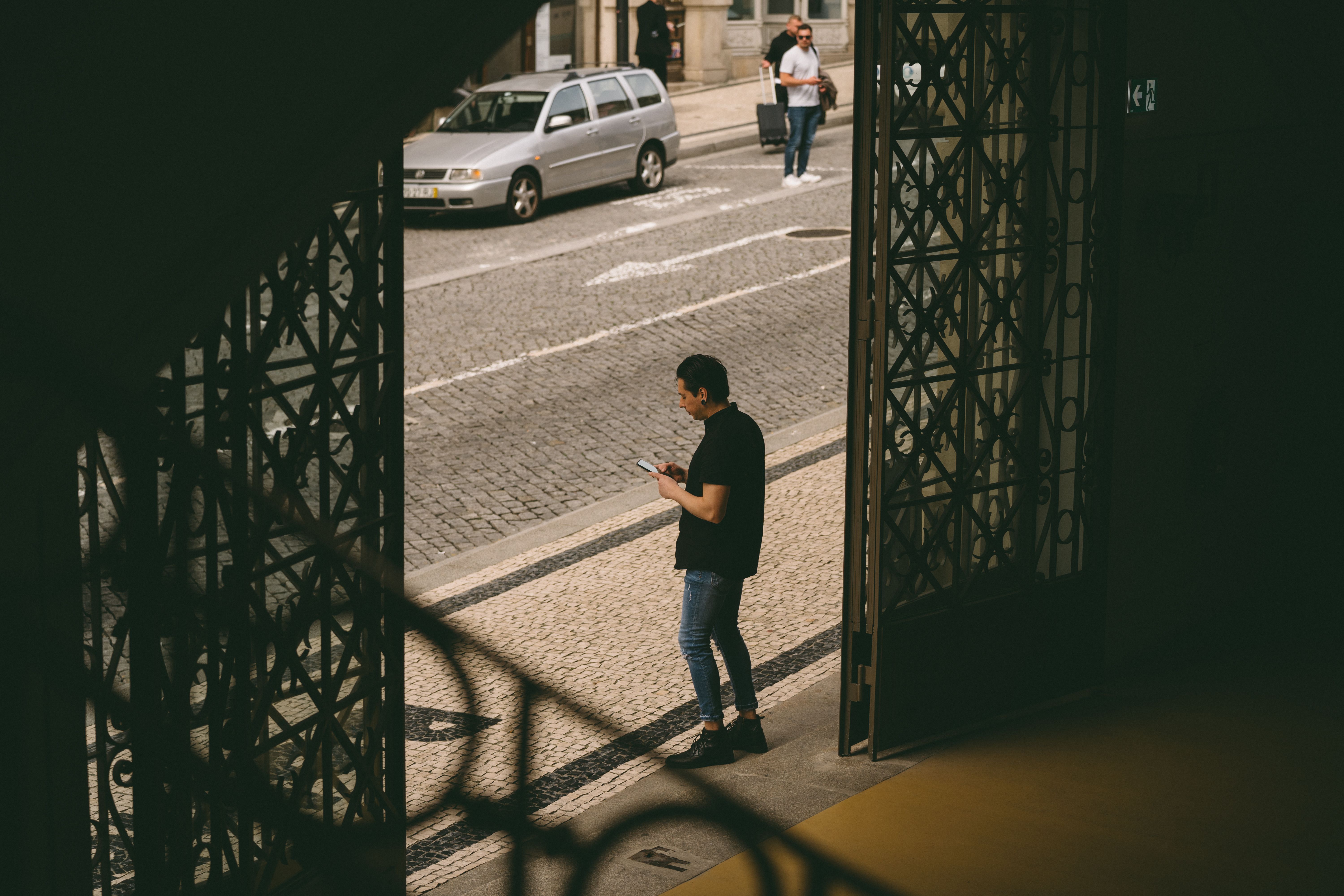 Man Standing with Smartphone on Sidewalk · Free Stock Photo