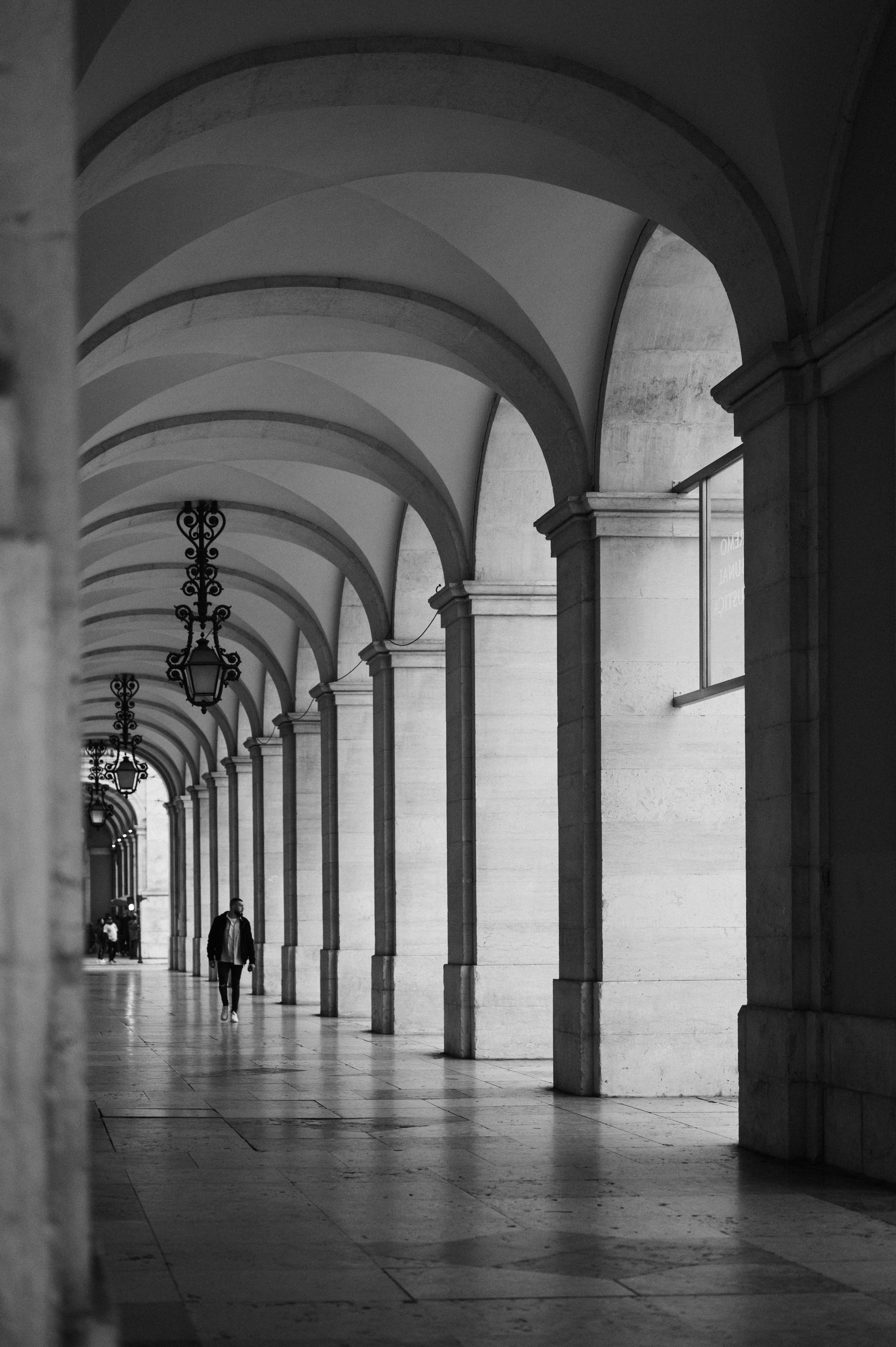 Person Walking Through Hallway of a Classical Building with Columns in ...