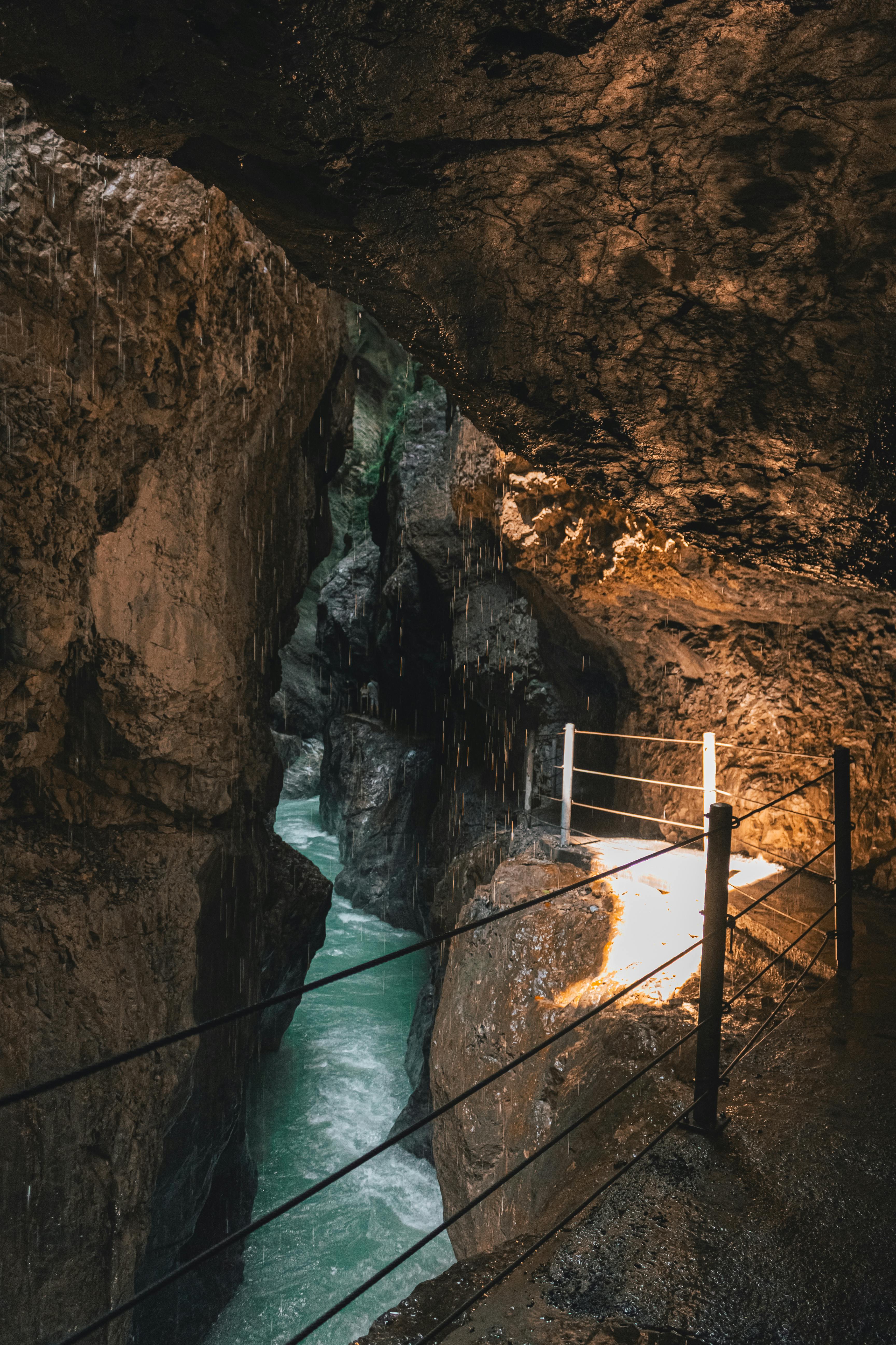 A cave with a railing and a river · Free Stock Photo