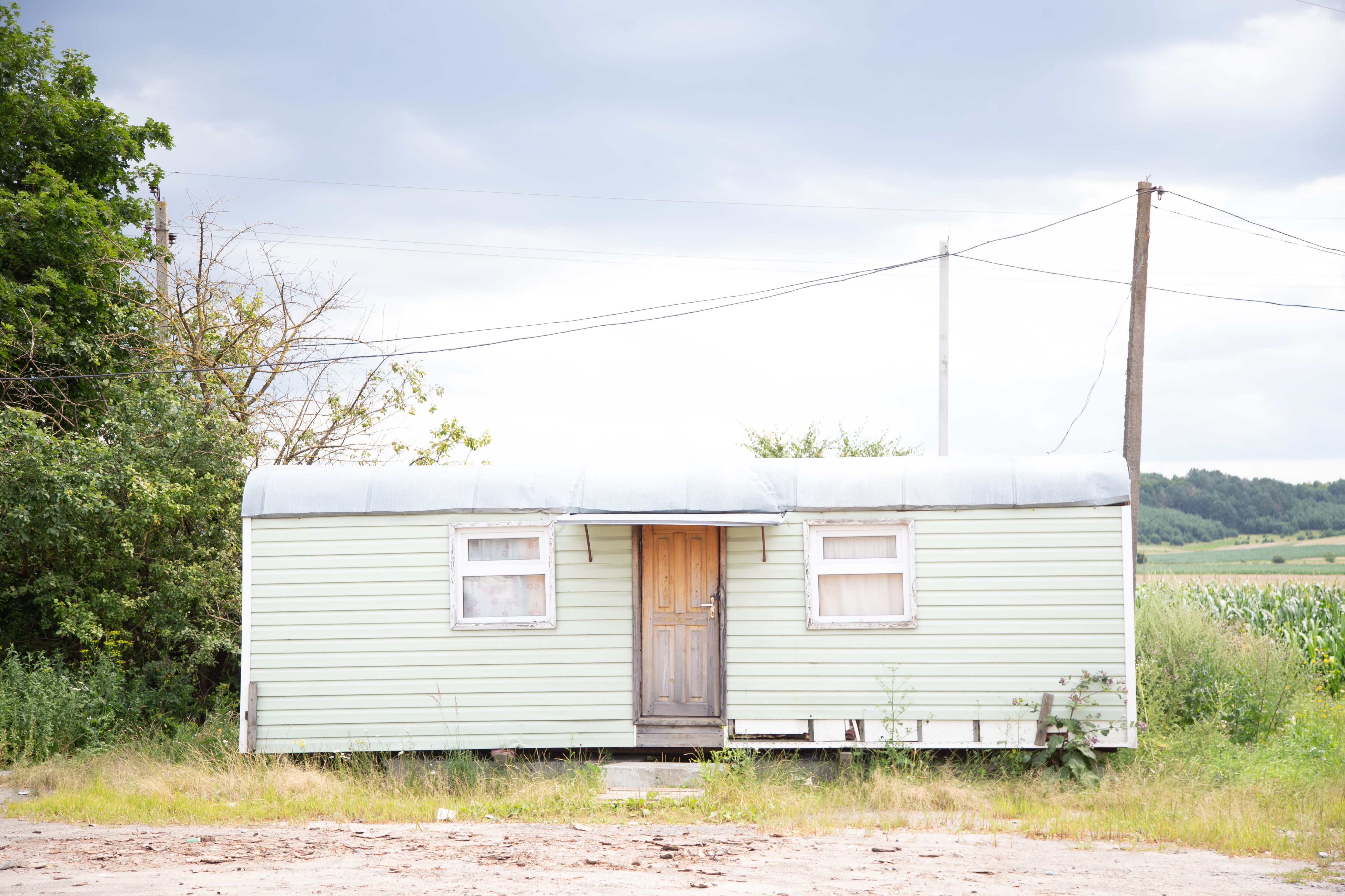A small green trailer sitting in the middle of a field · Free Stock Photo