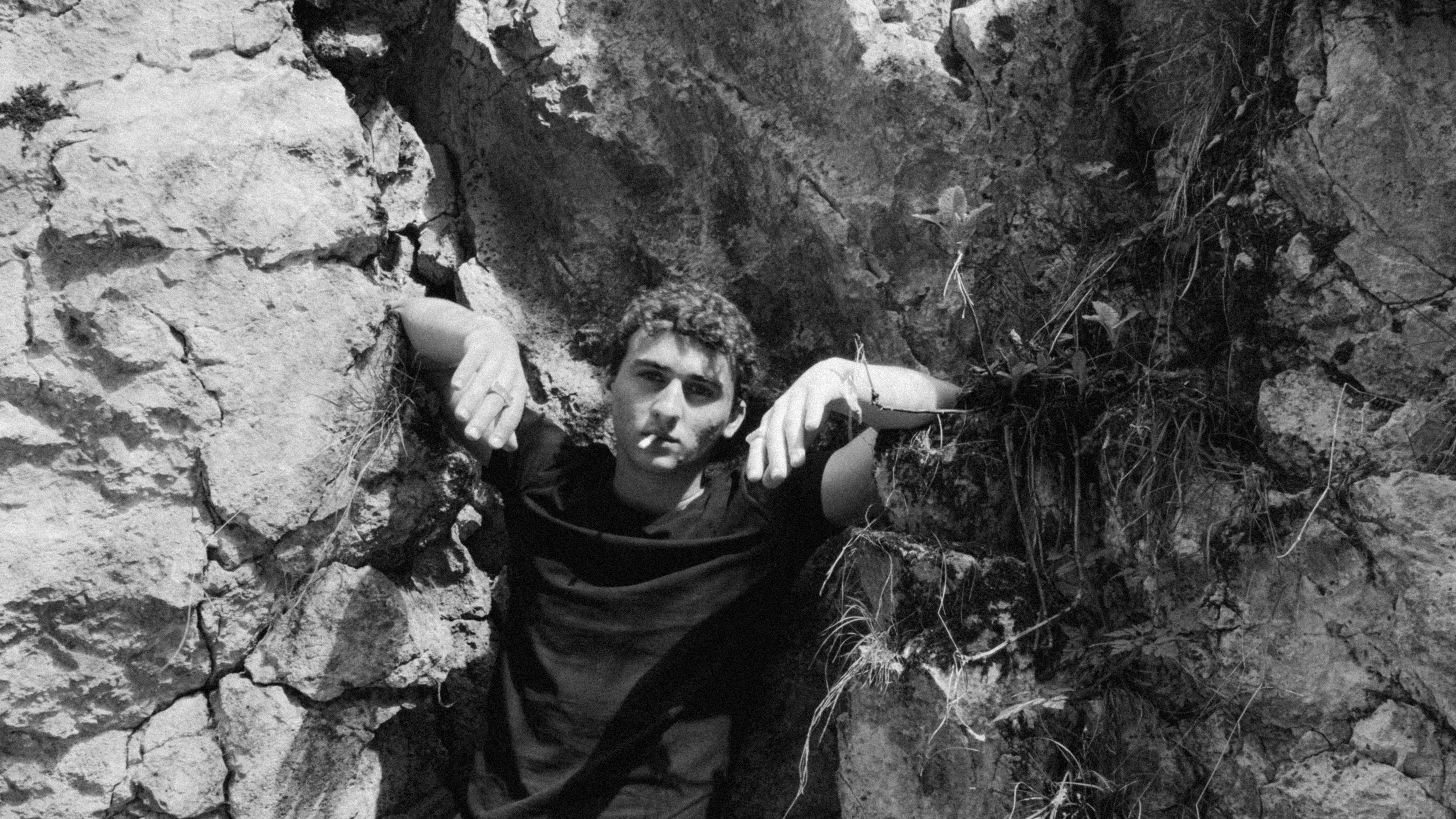 A man leaning against a rock with his arms crossed · Free Stock Photo