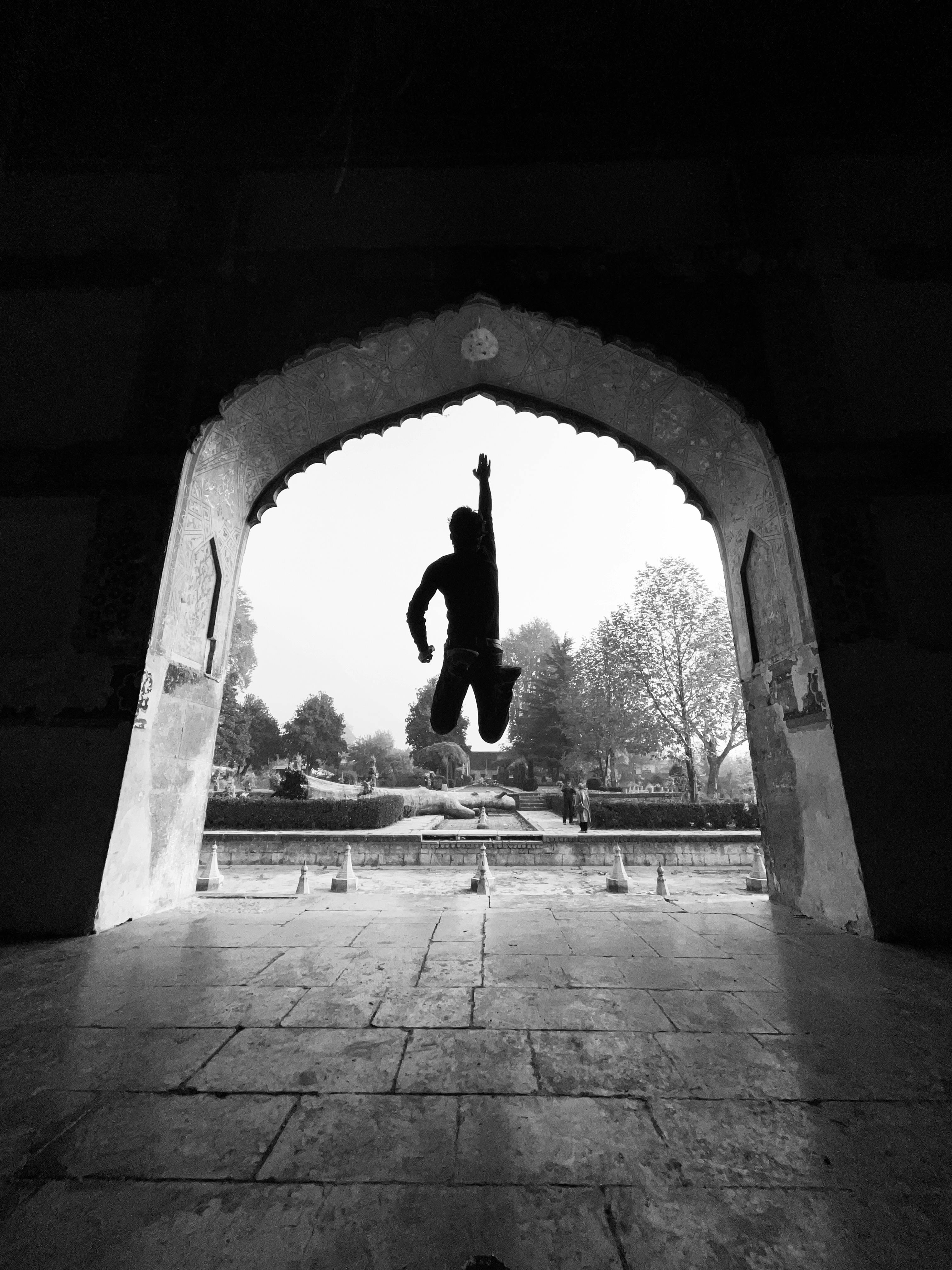 Silhouette of a Person Jumping under an Arch · Free Stock Photo