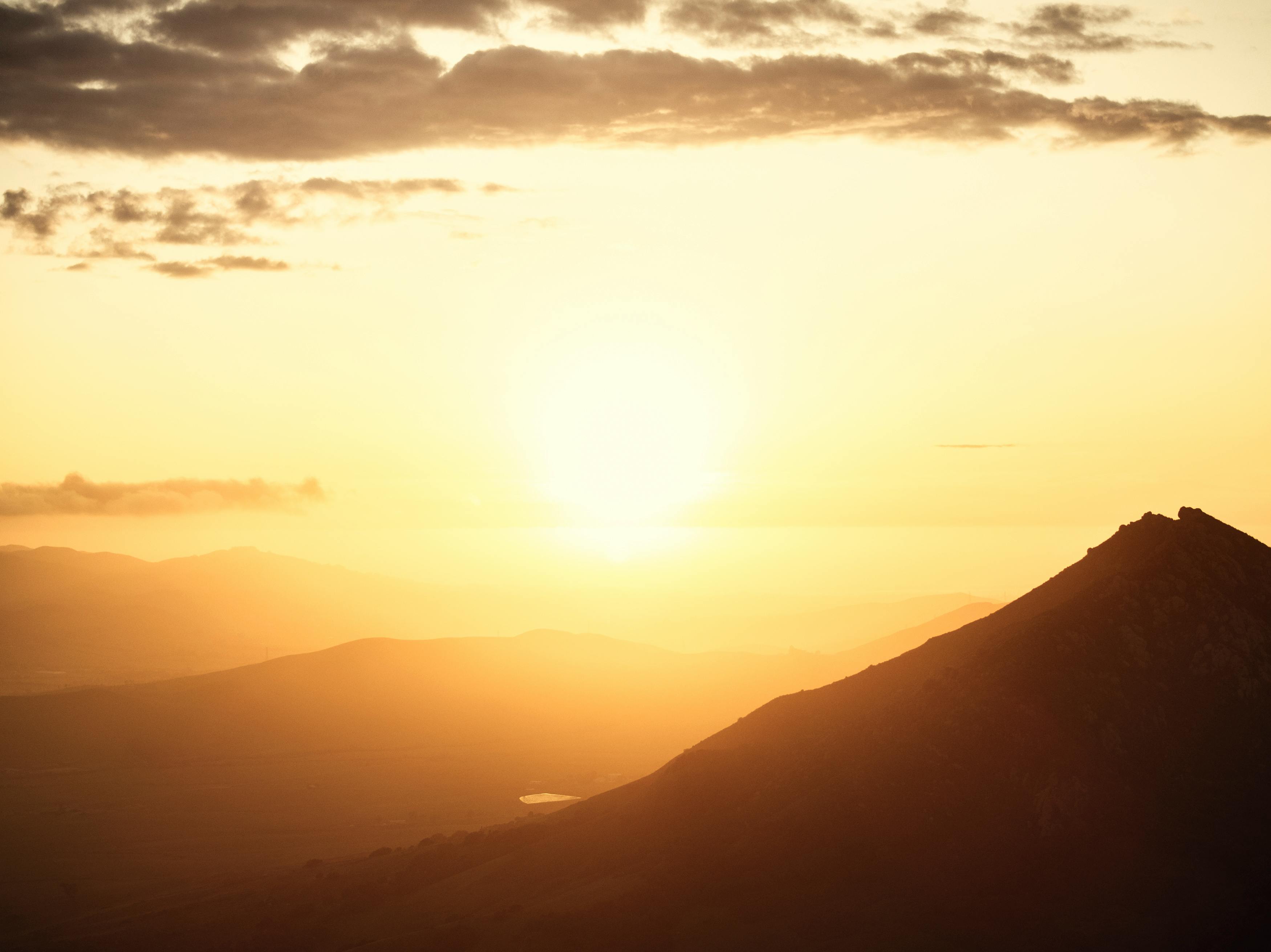 Sunlight over Mountain Silhouette at Sunset · Free Stock Photo