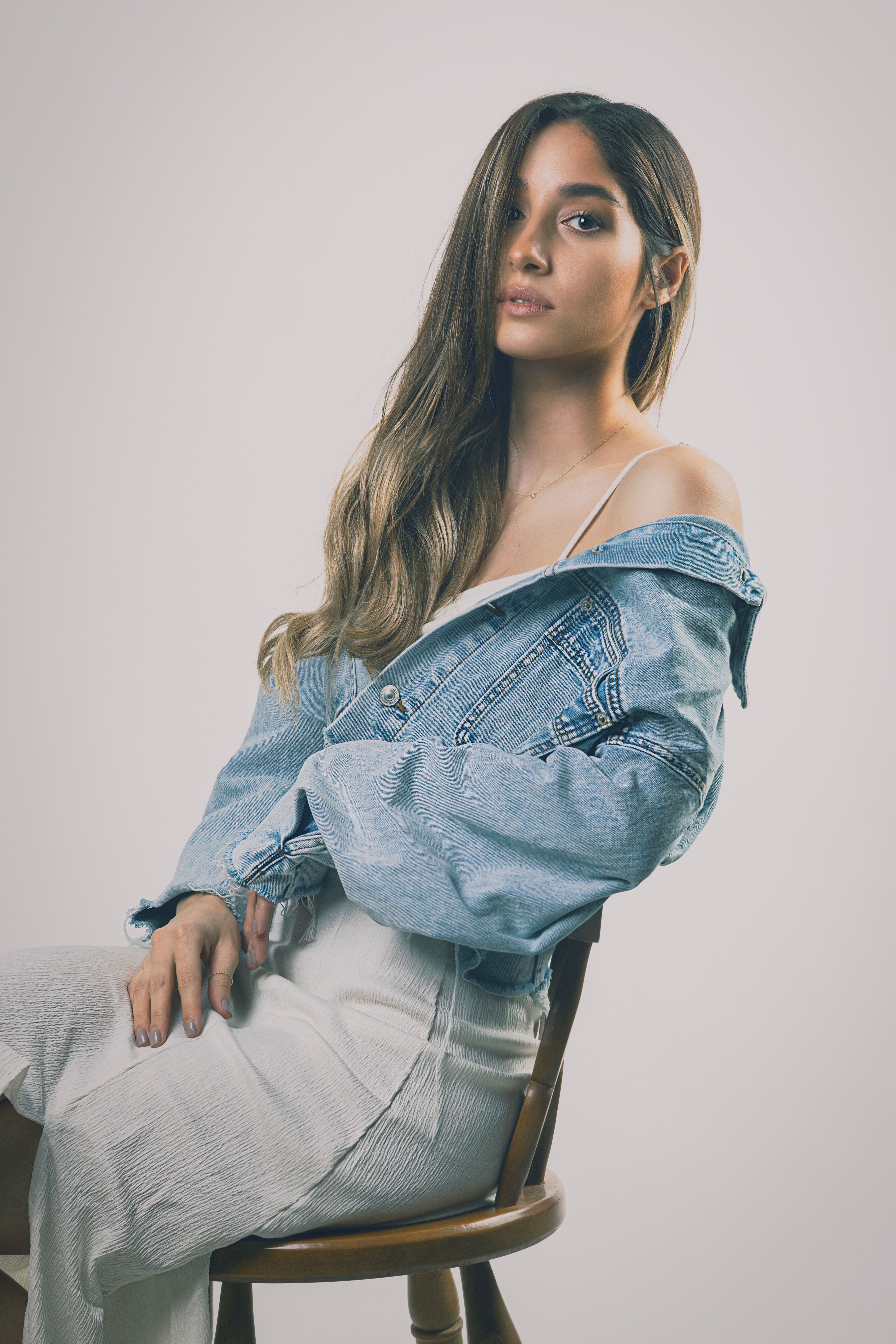 A woman sitting on a chair wearing a denim jacket · Free Stock Photo