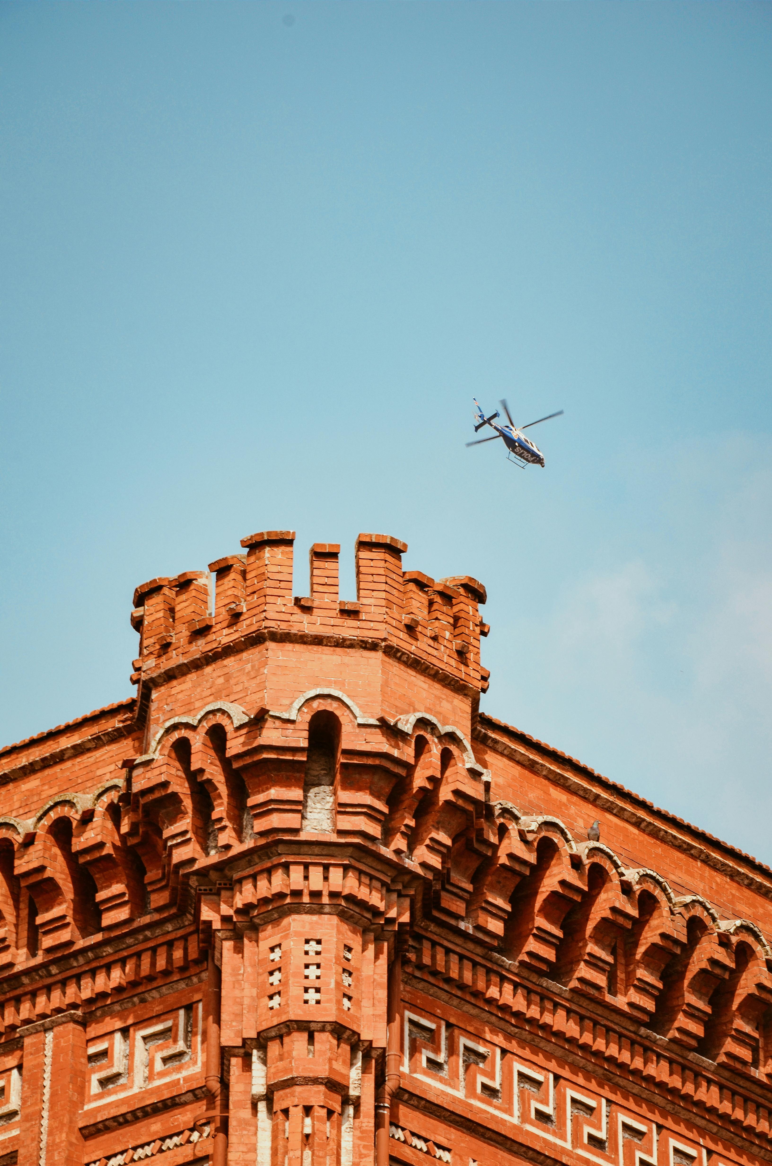 Helicopter Flying Over Brown Building With Turret · Free Stock Photo