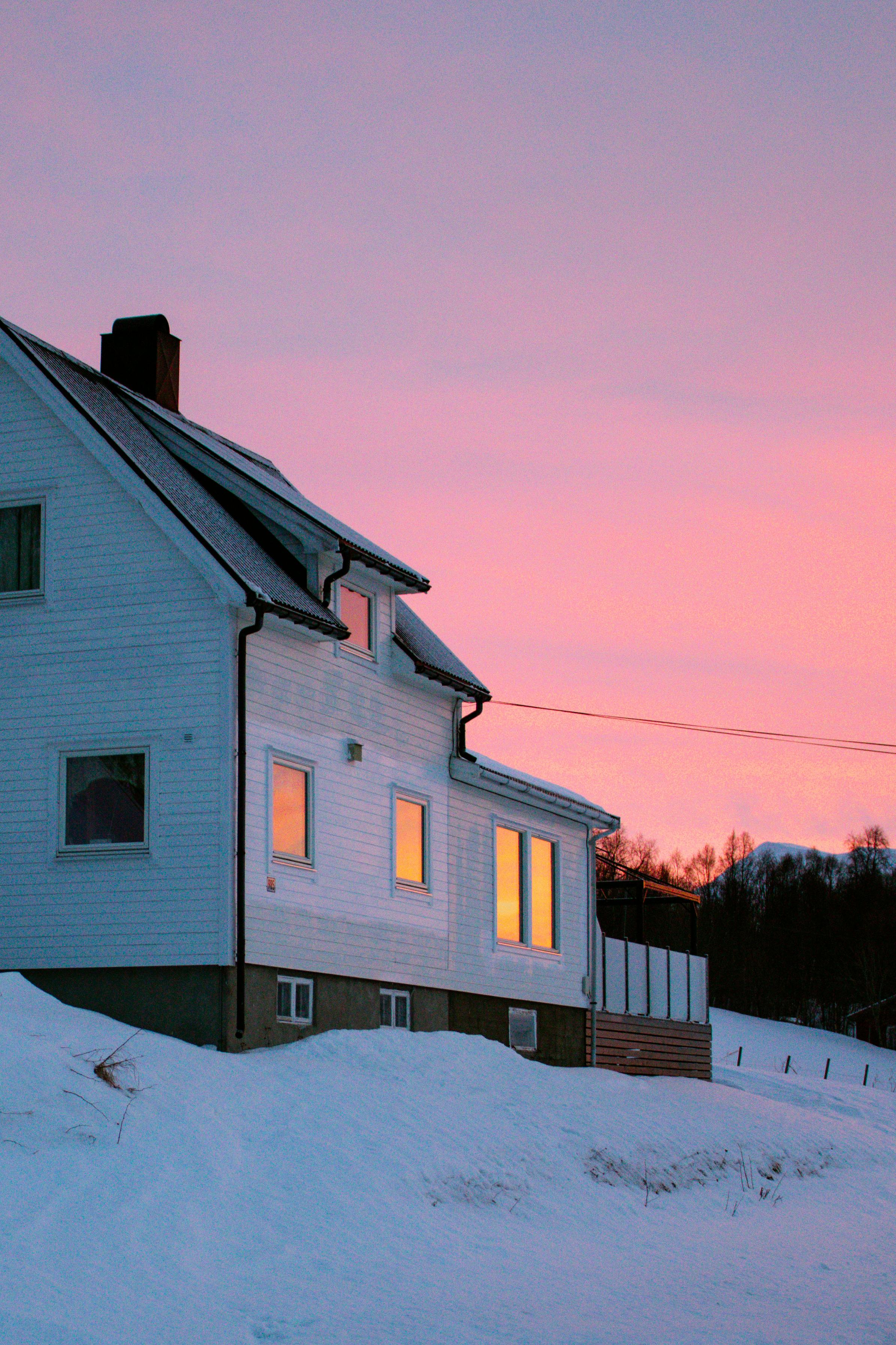A house is shown in the snow at sunset · Free Stock Photo