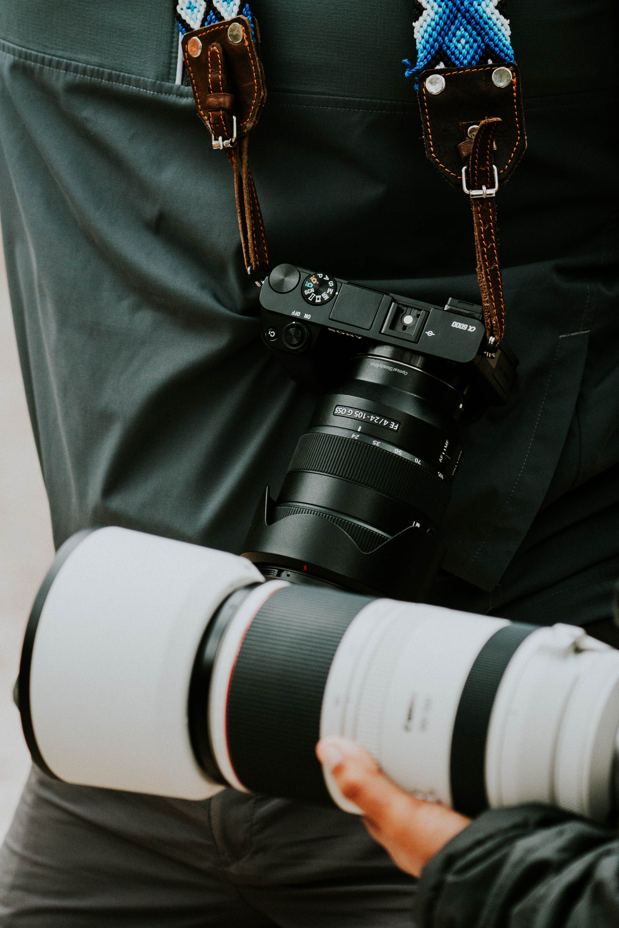 A person holding a camera with a strap · Free Stock Photo