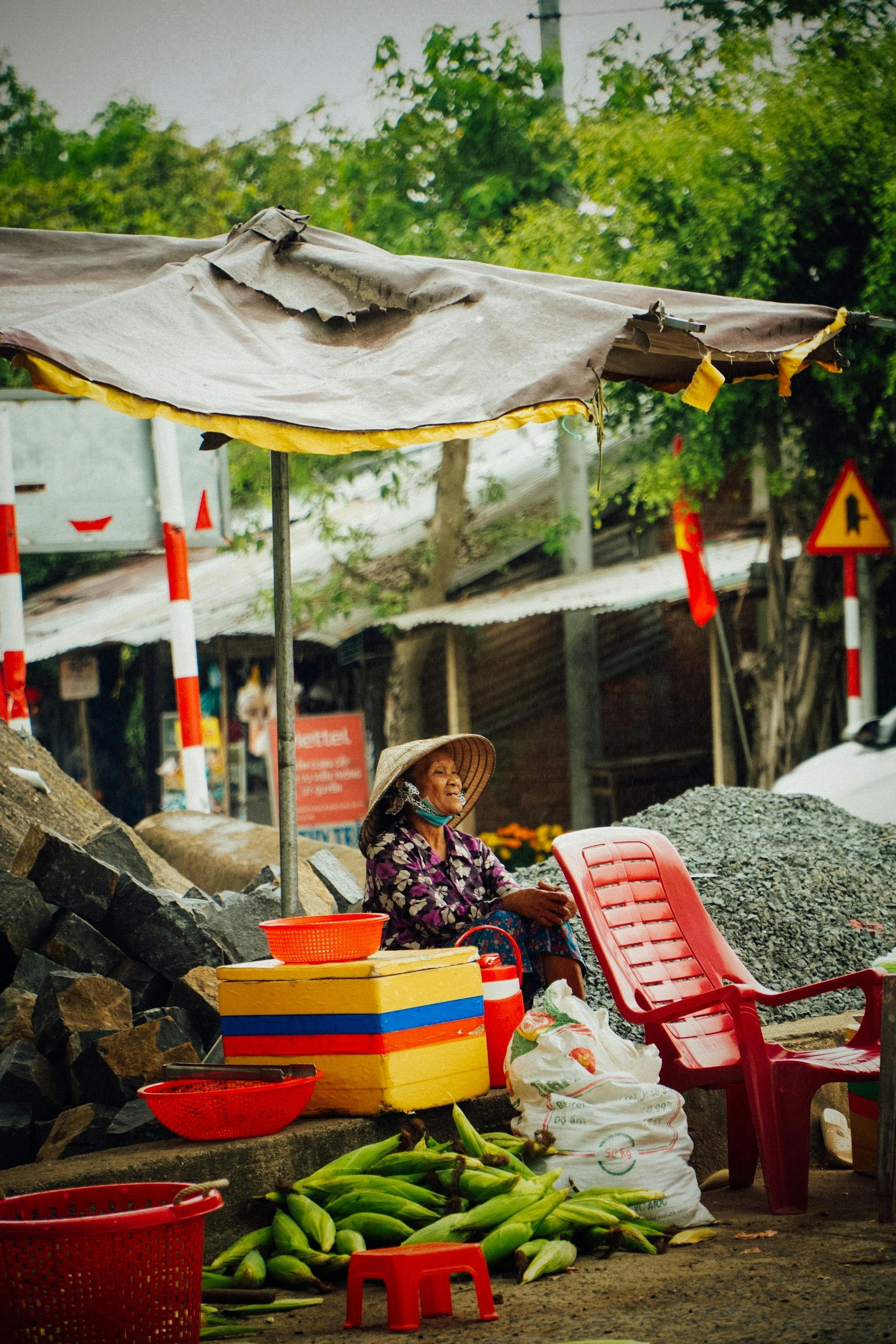 A Colorful Market Stall With A Vendor Smiling While Arranging Fresh ...