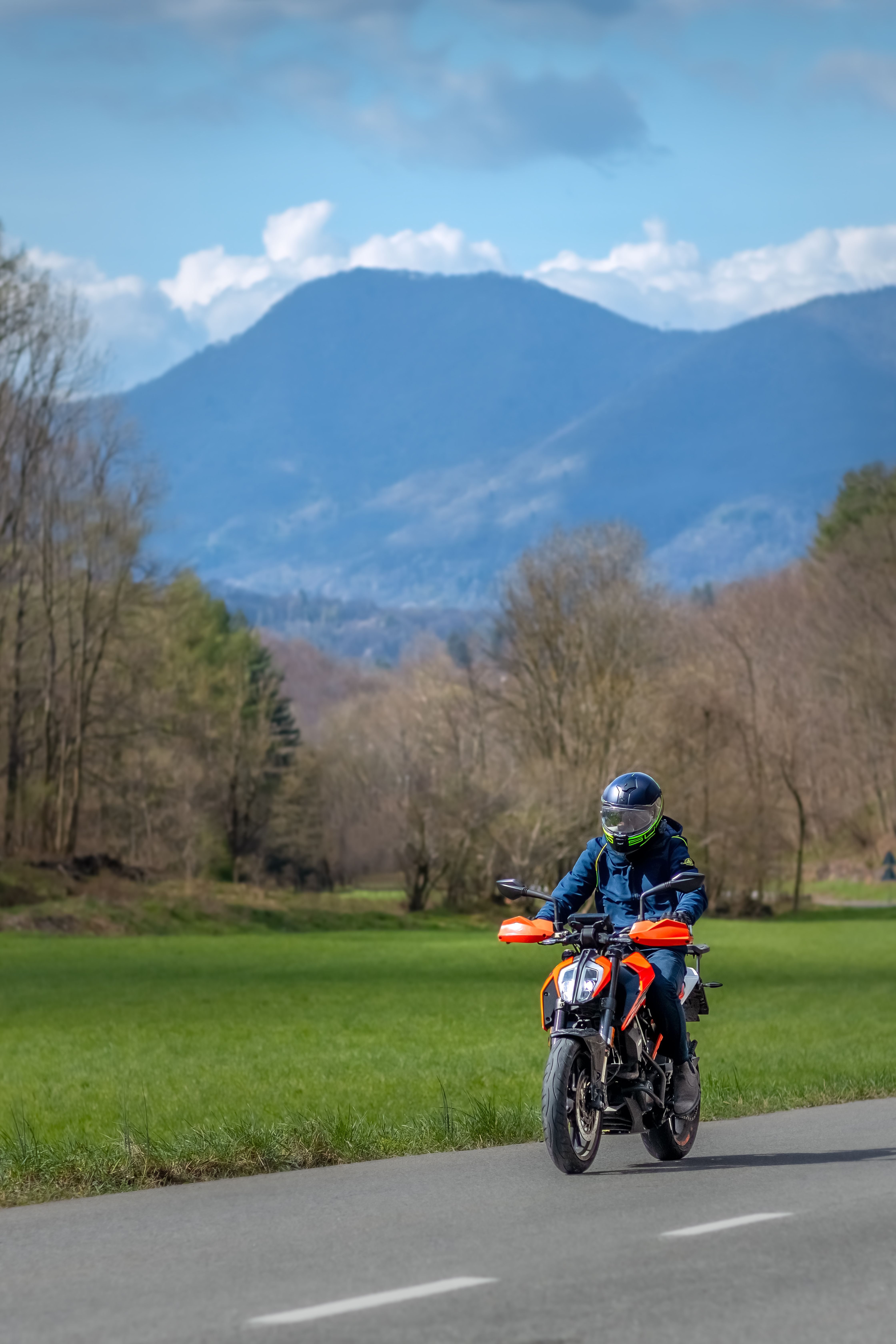A person riding a motorcycle on a road with mountains in the background ...