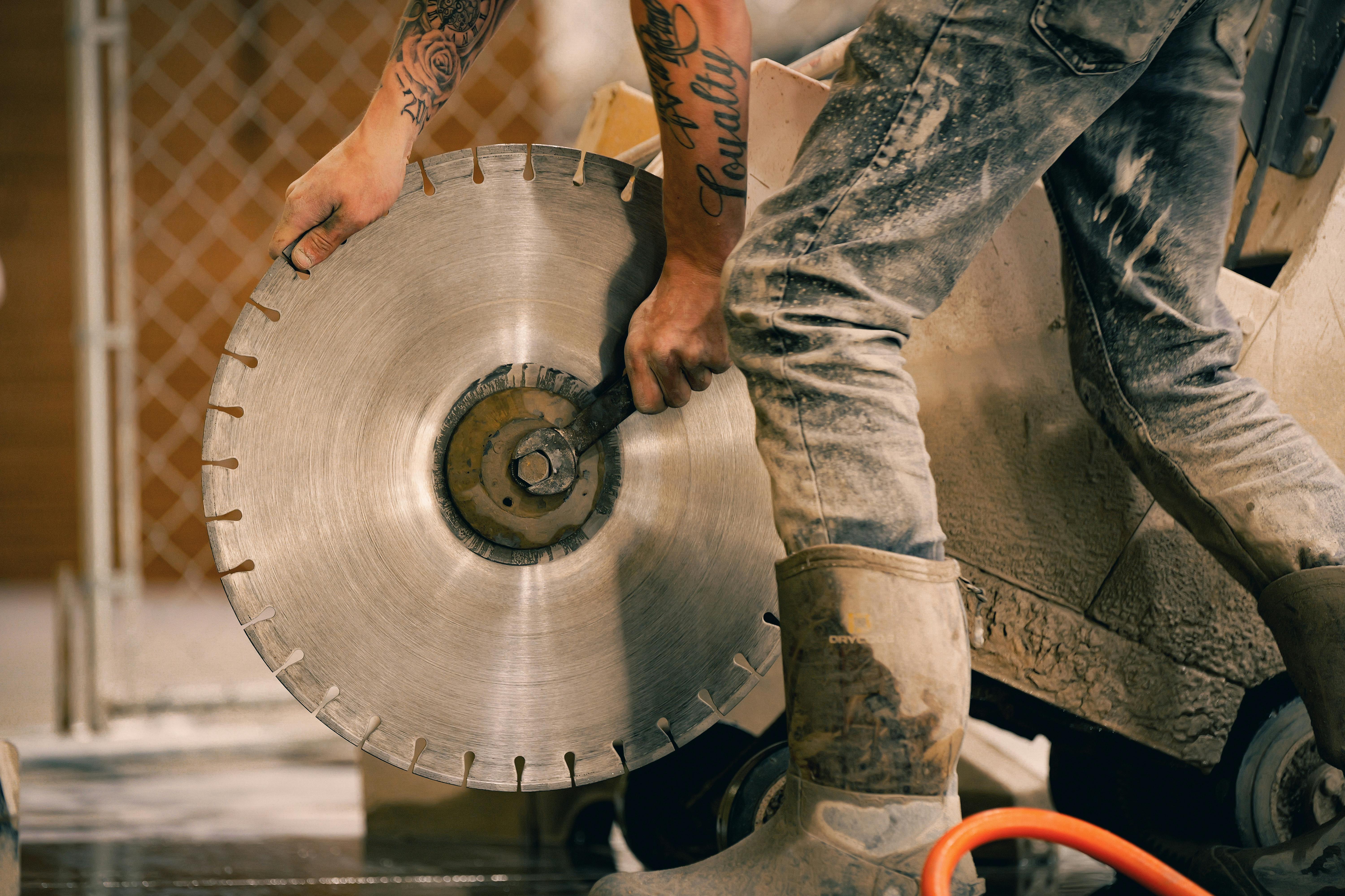 Close-up of a Man Using a Wrench on a Diamond Saw · Free Stock Photo