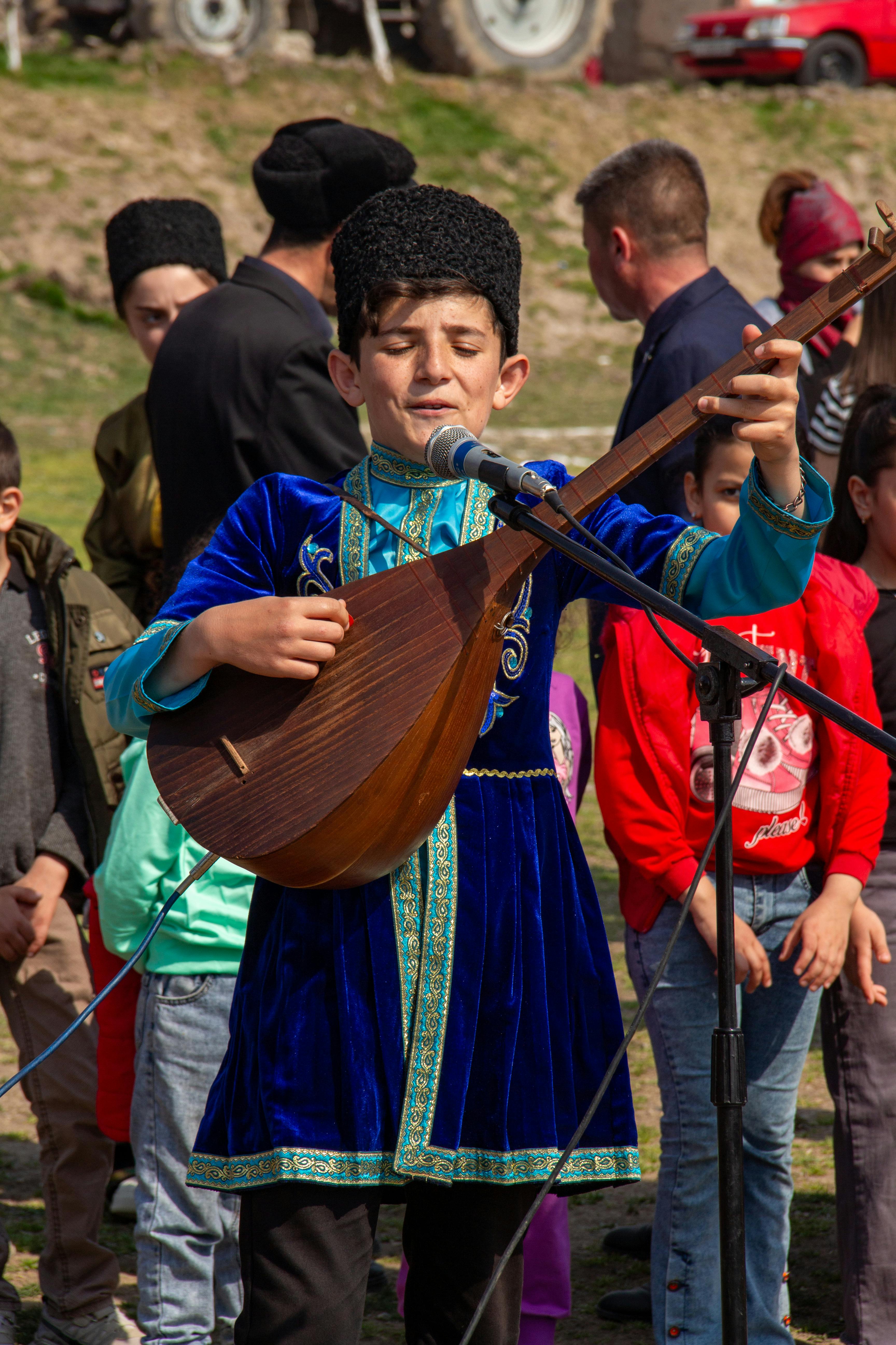 Boy Playing Traditional String Instrument on Stage · Free Stock Photo