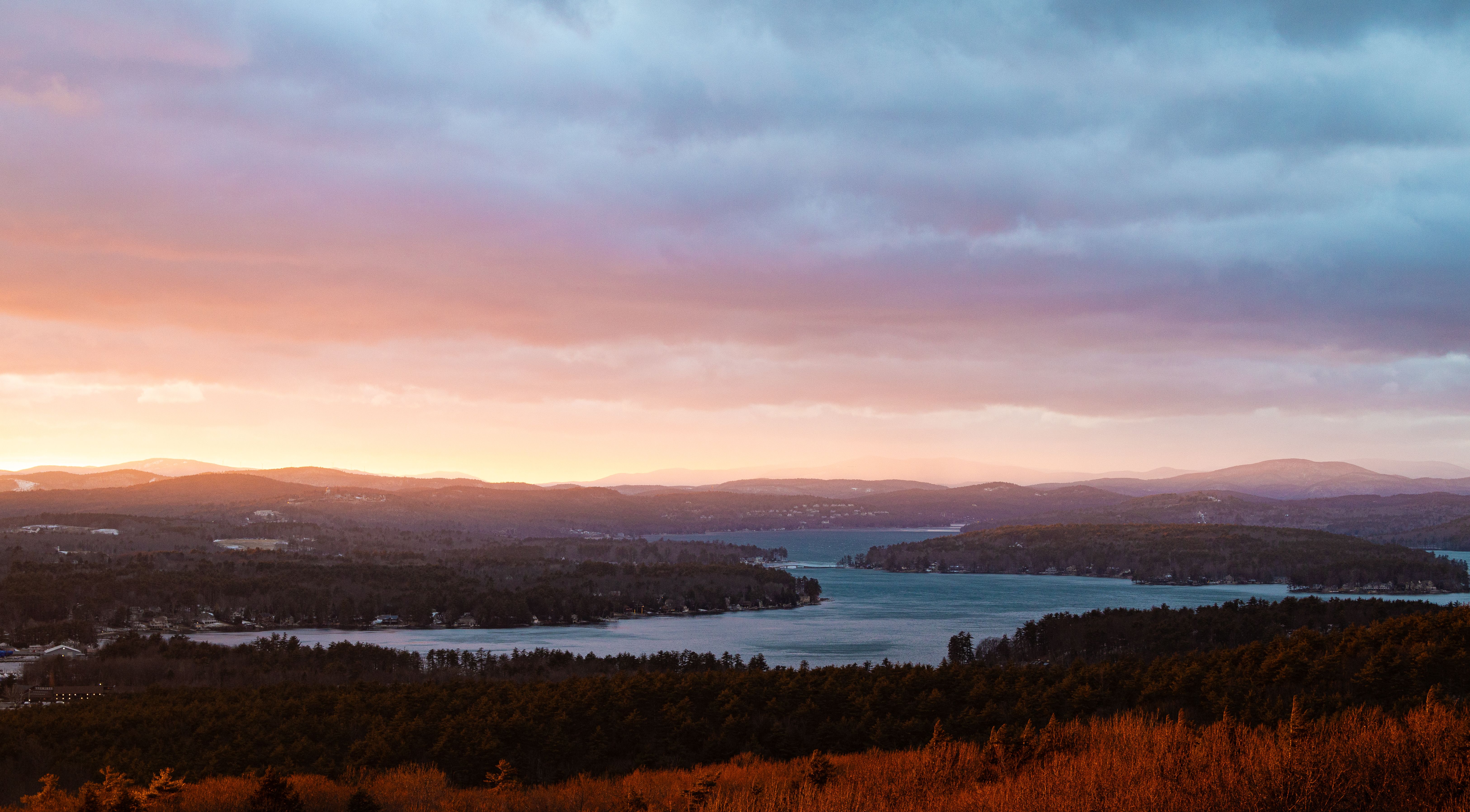 A sunset over a lake and hills · Free Stock Photo