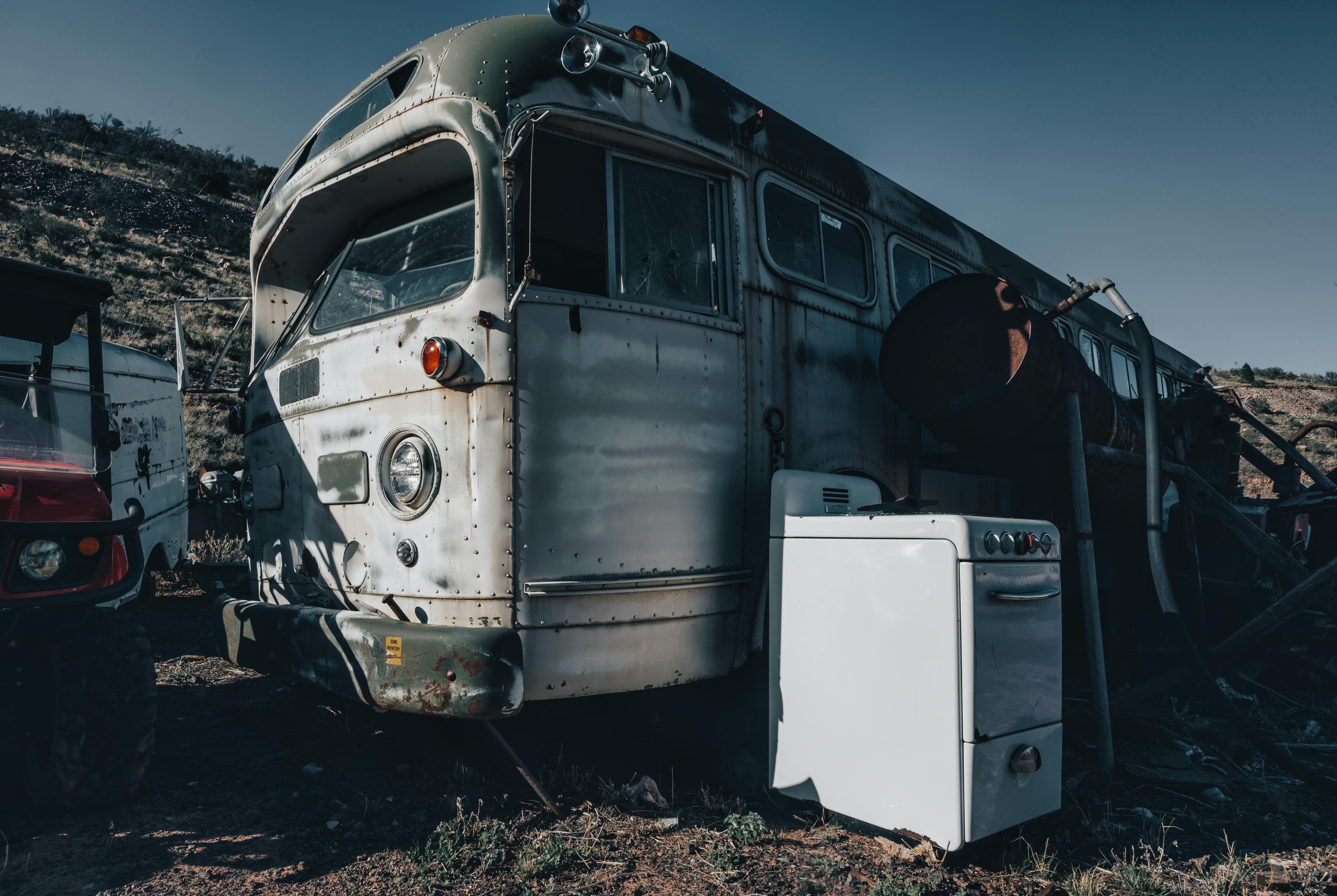 A bus and a refrigerator sitting in the dirt · Free Stock Photo