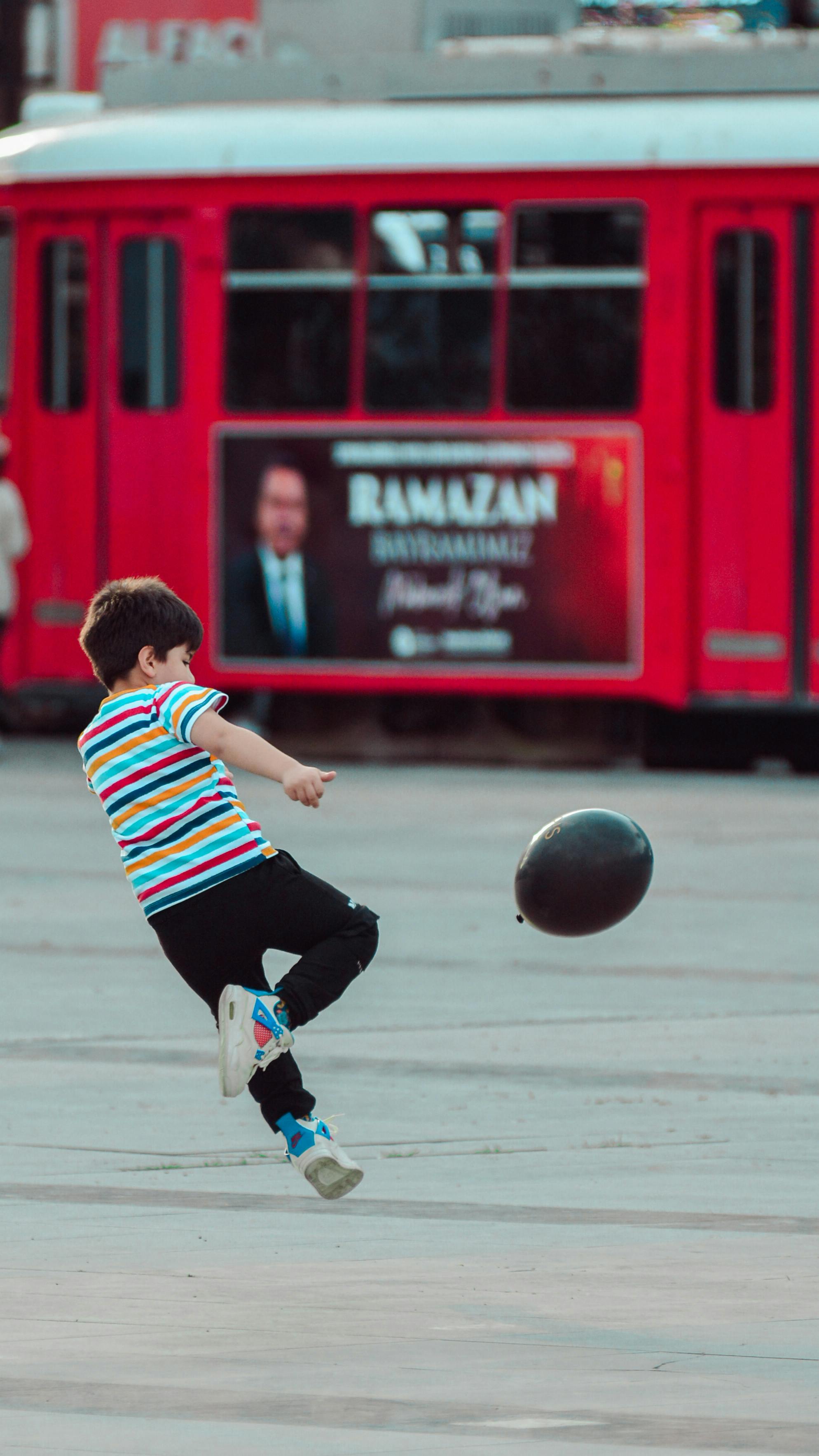 Boy Kicking Black Balloon Against Urban Background · Free Stock Photo