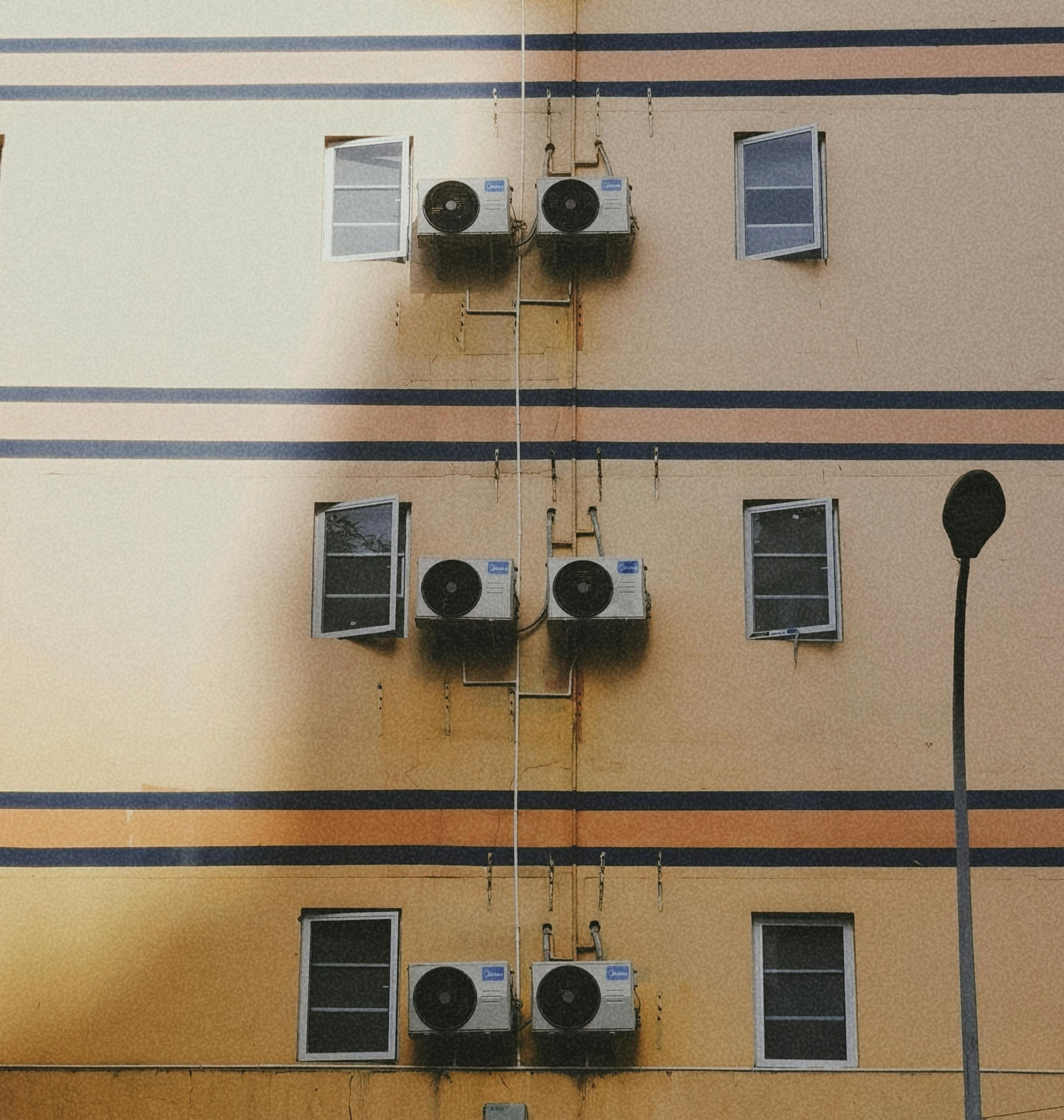 A yellow building with several air conditioning units · Free Stock Photo