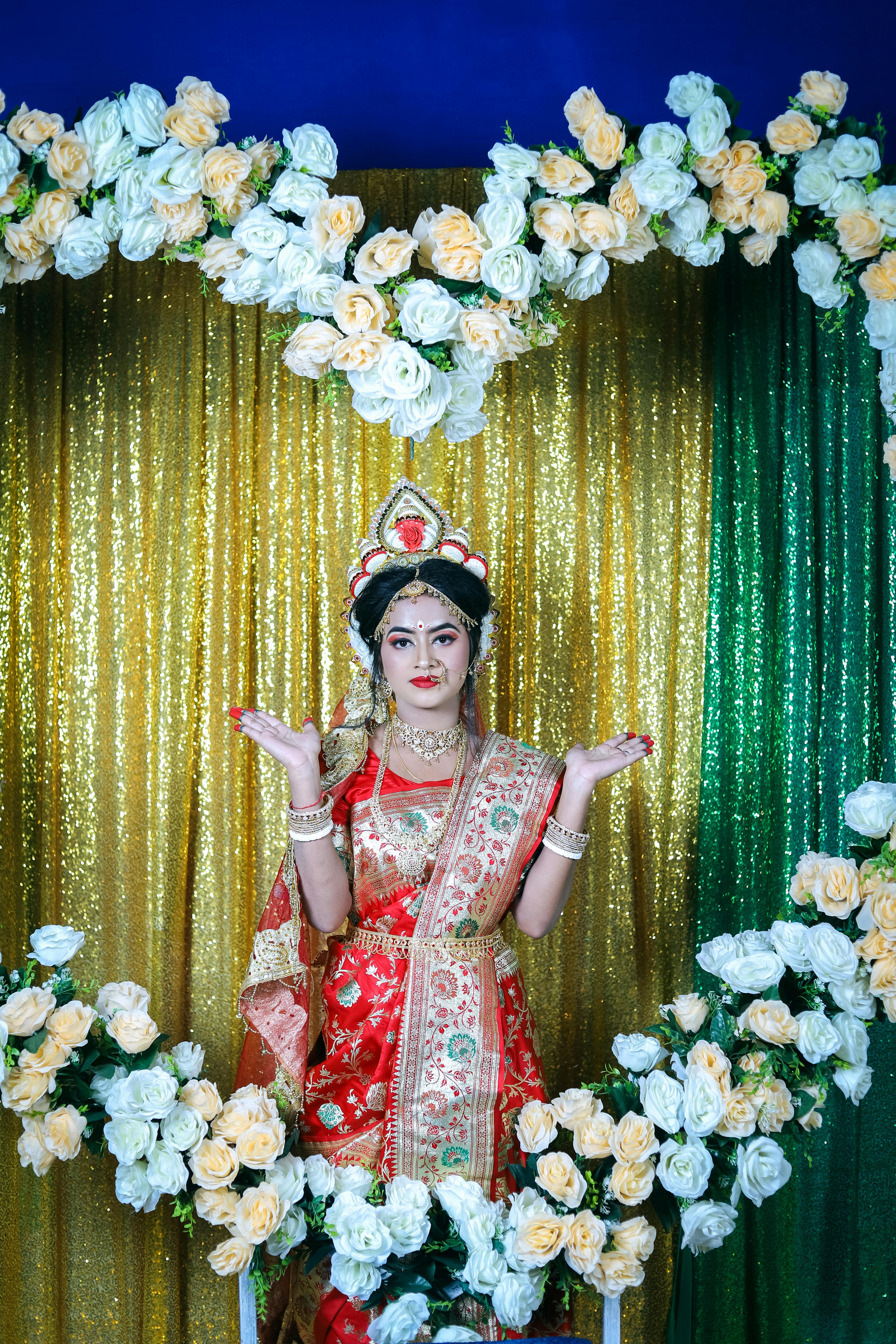 A woman in traditional dress posing in front of a floral heart shaped ...