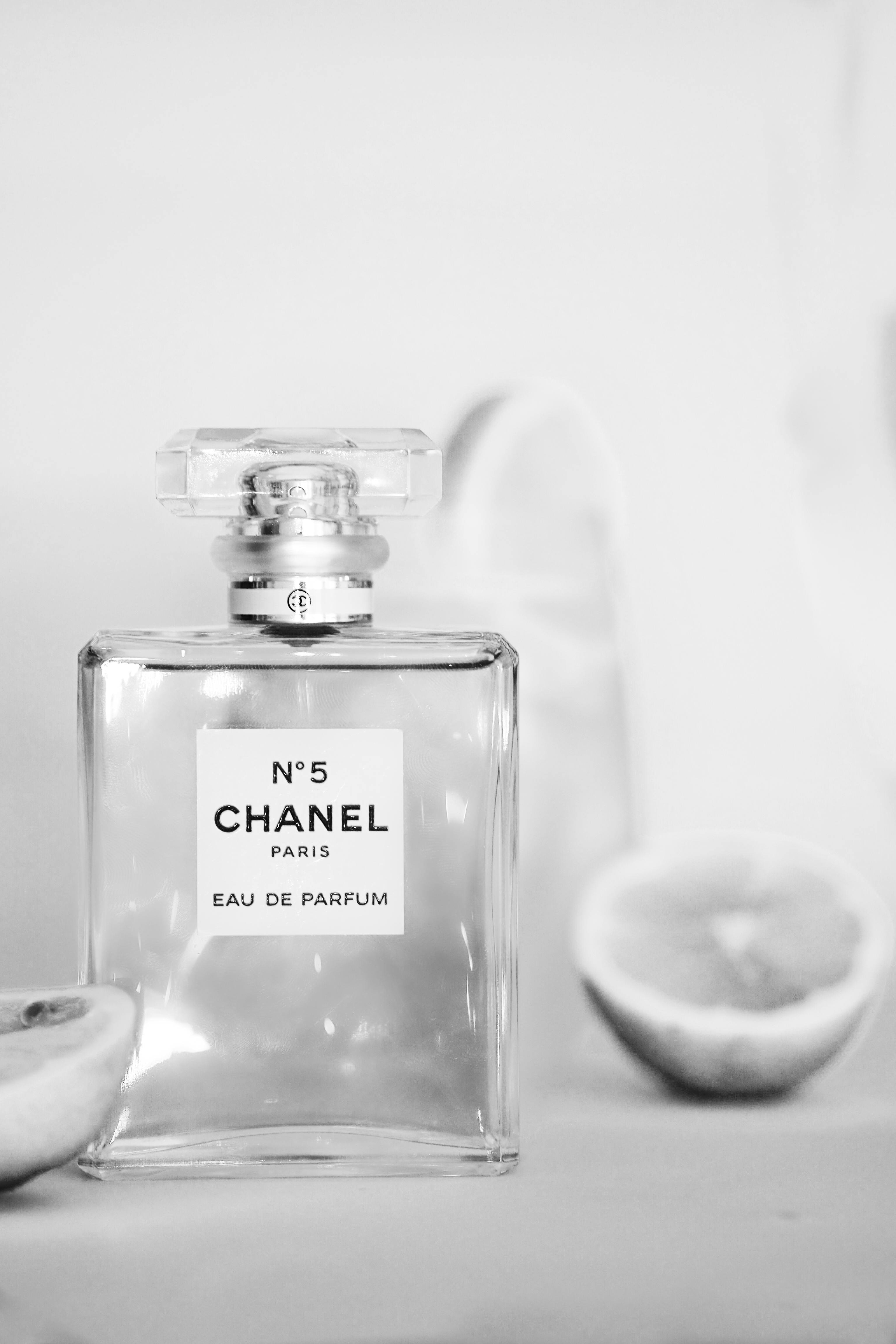 A bottle of chanel perfume sits on a table next to some lemons · Free ...