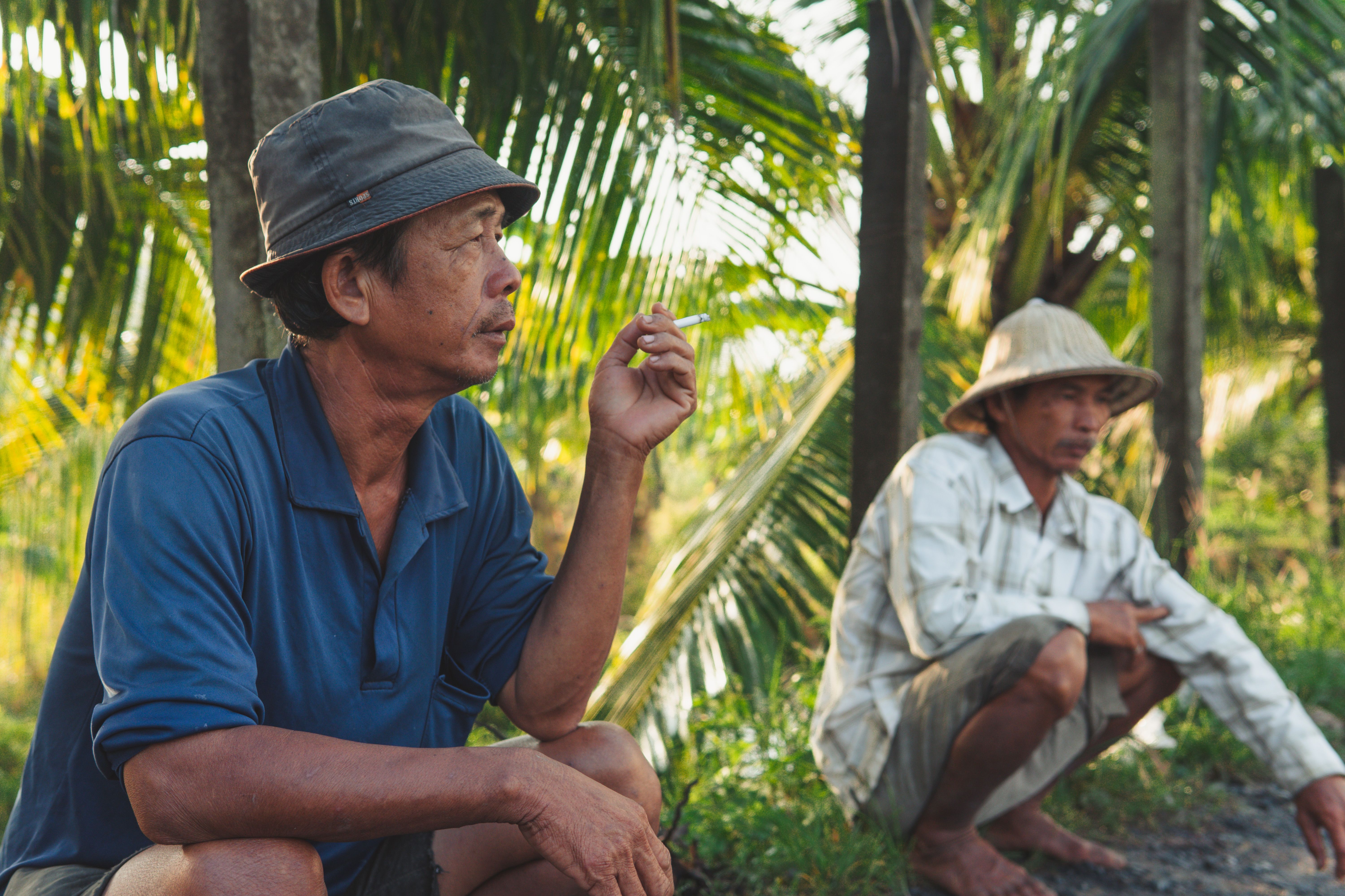 Two men sitting on the ground smoking cigarettes · Free Stock Photo